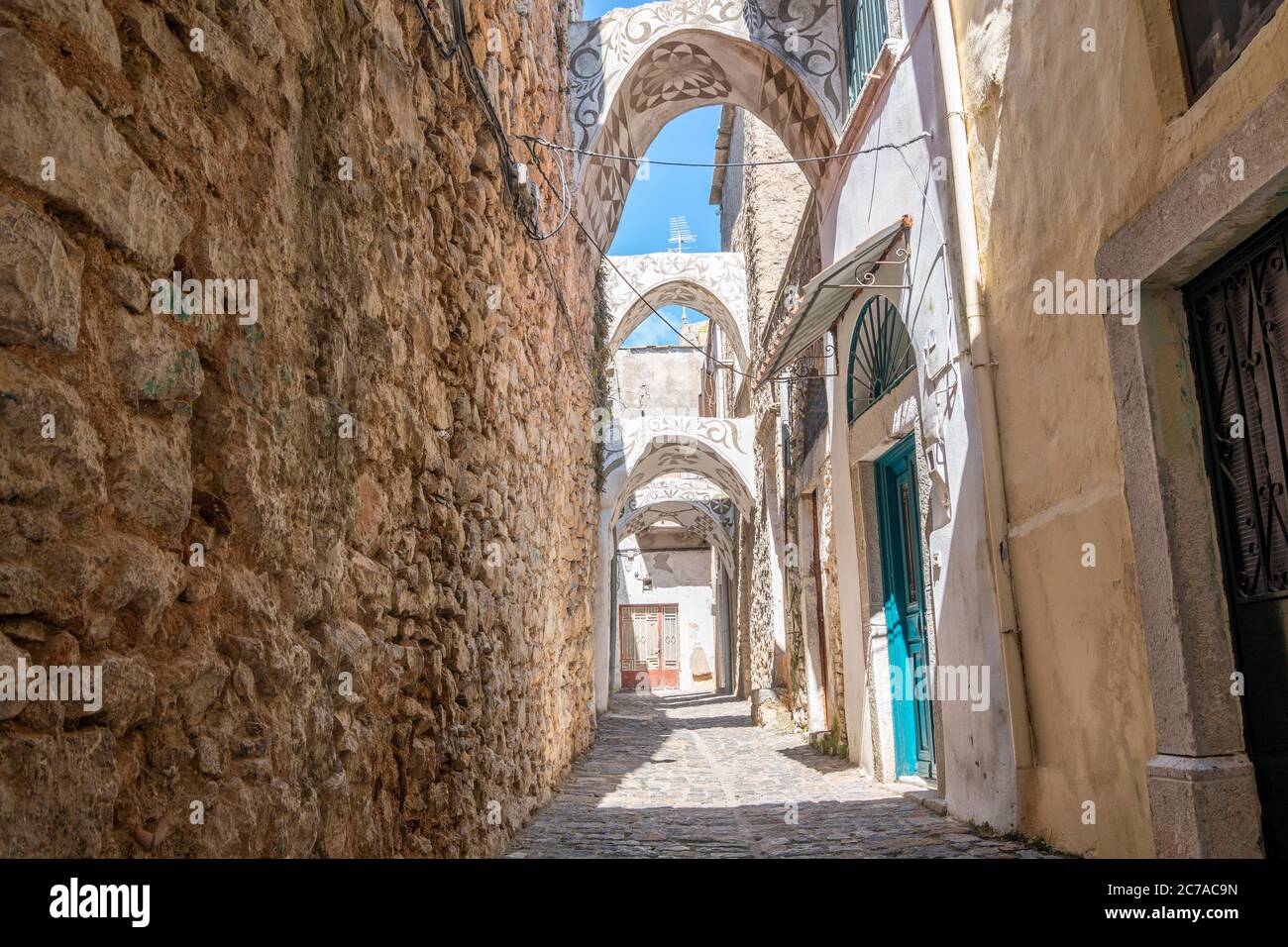 A narrow alley between stone houses with traditional geometric patterns ...