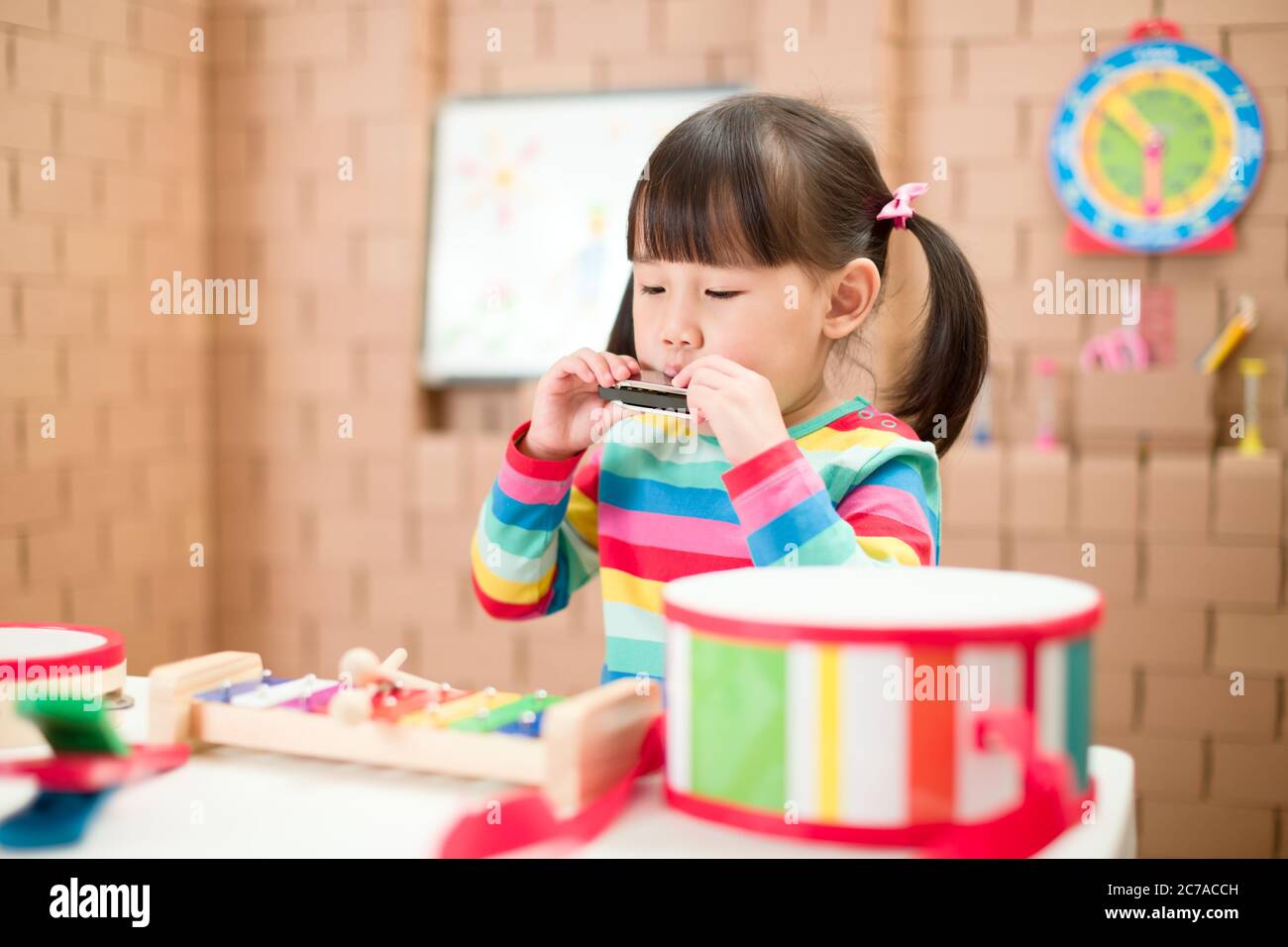 toddler girl play harmonica at home for homeschooling Stock Photo - Alamy