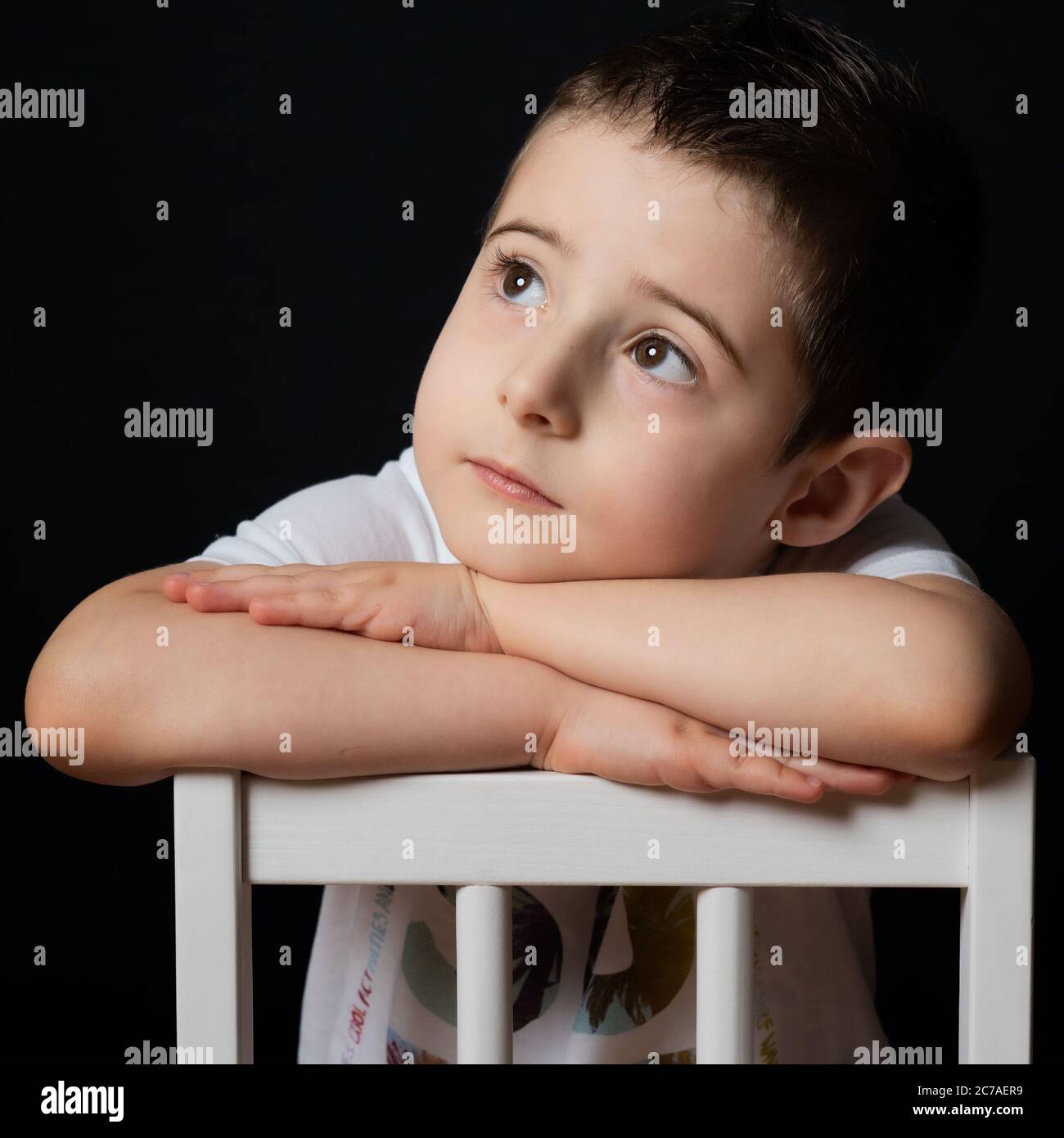 Low key portrait of young boy isolated on black background. Dreaming ...