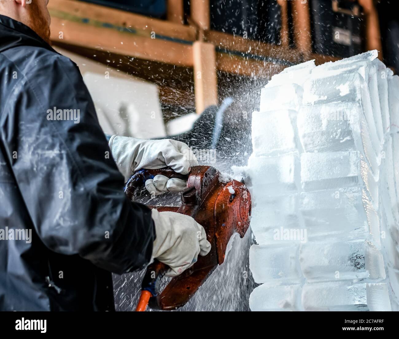 Ice carver sculpting block of ice with electric power chainsaw Stock ...