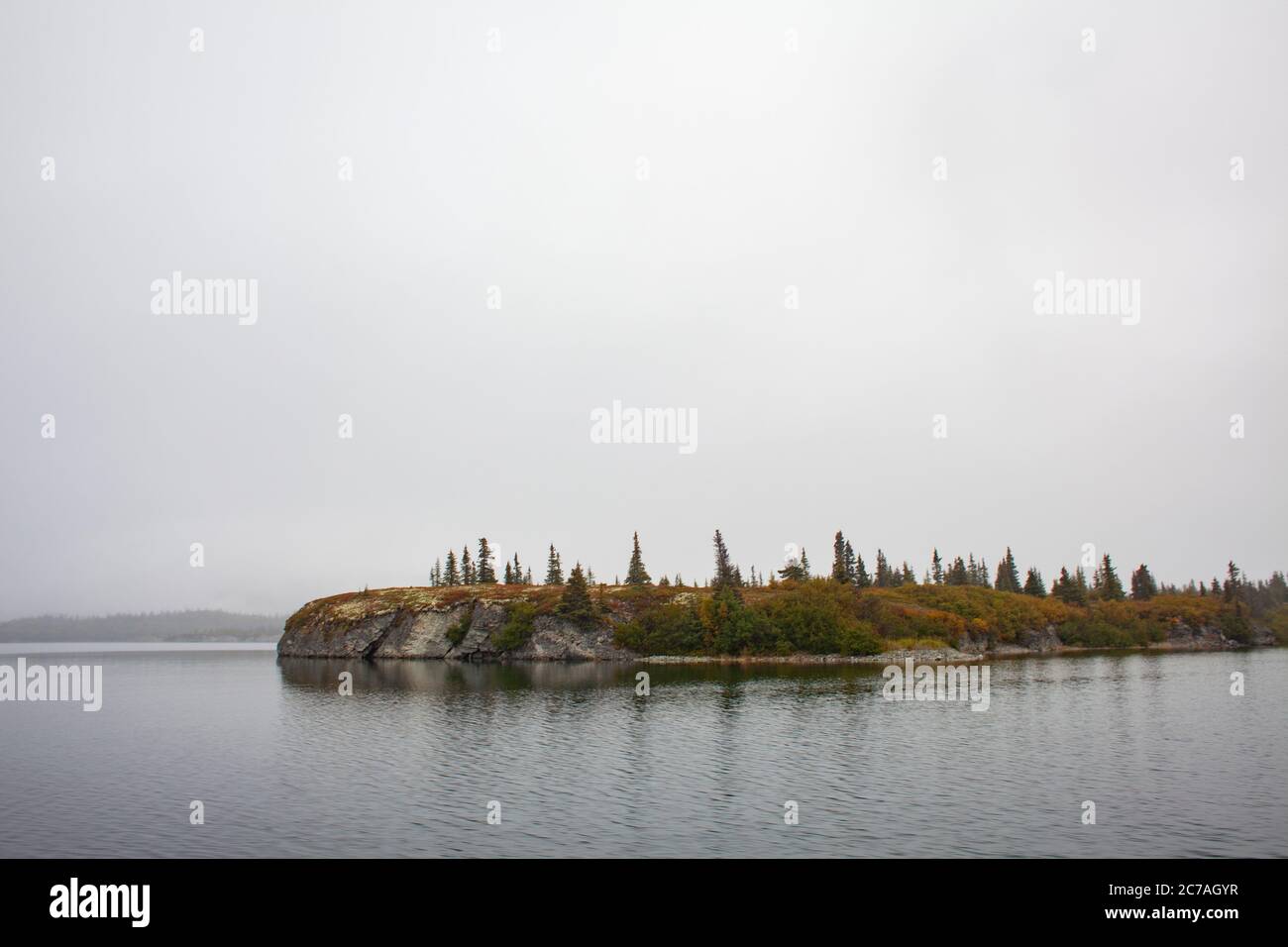 A serene, forested island sits surrounded by calm, misty waters in the ...