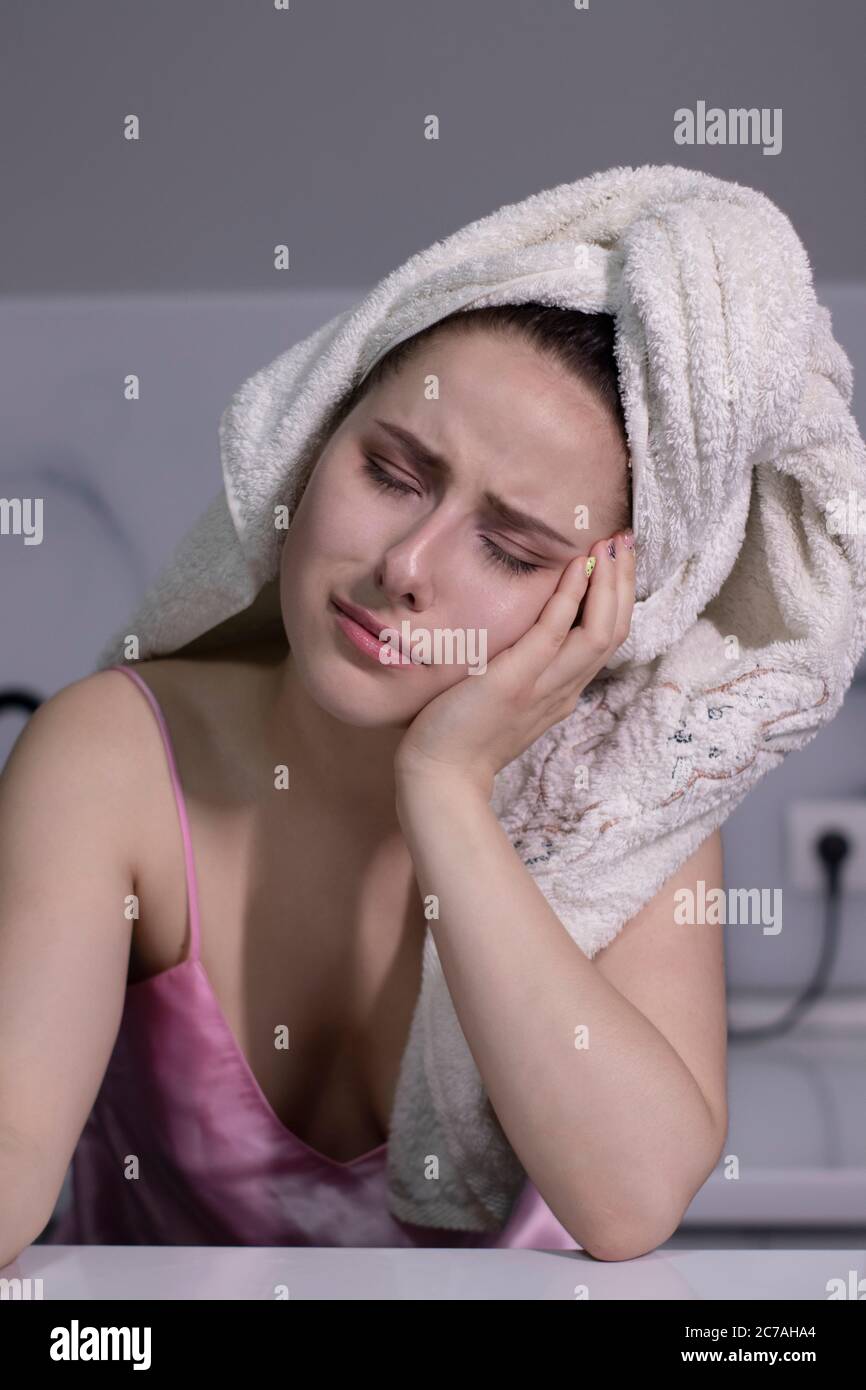 sad, attractive brunette girl - in pink pajamas and with a white towel ...