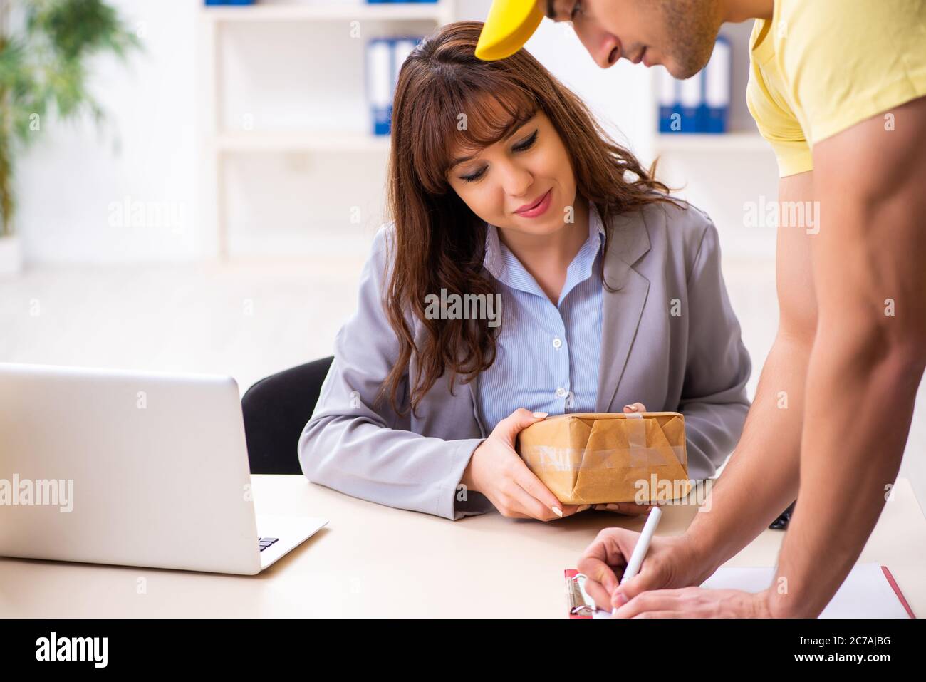 Young courier delivering parcel to the office Stock Photo - Alamy