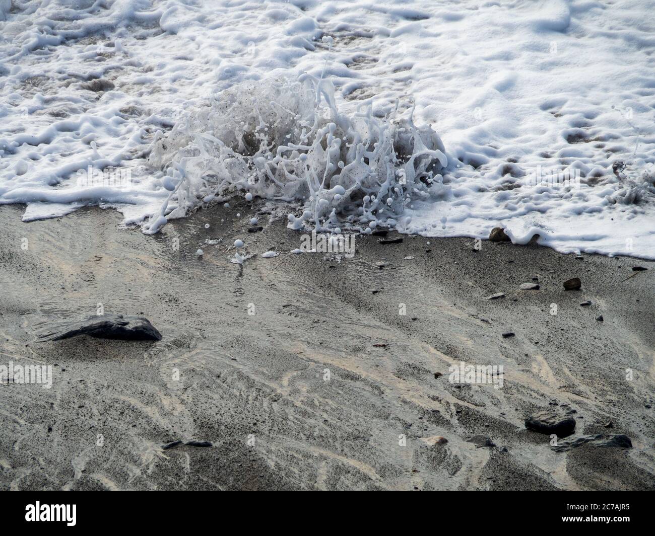 Foamy white salt water splashing up as it rolls onto the beach Stock ...