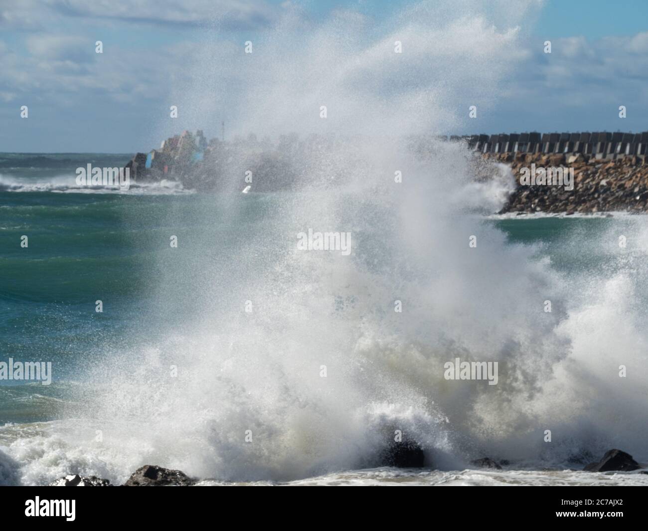 Closeup ocean waves crashing into rocks and spraying up in an explosion ...