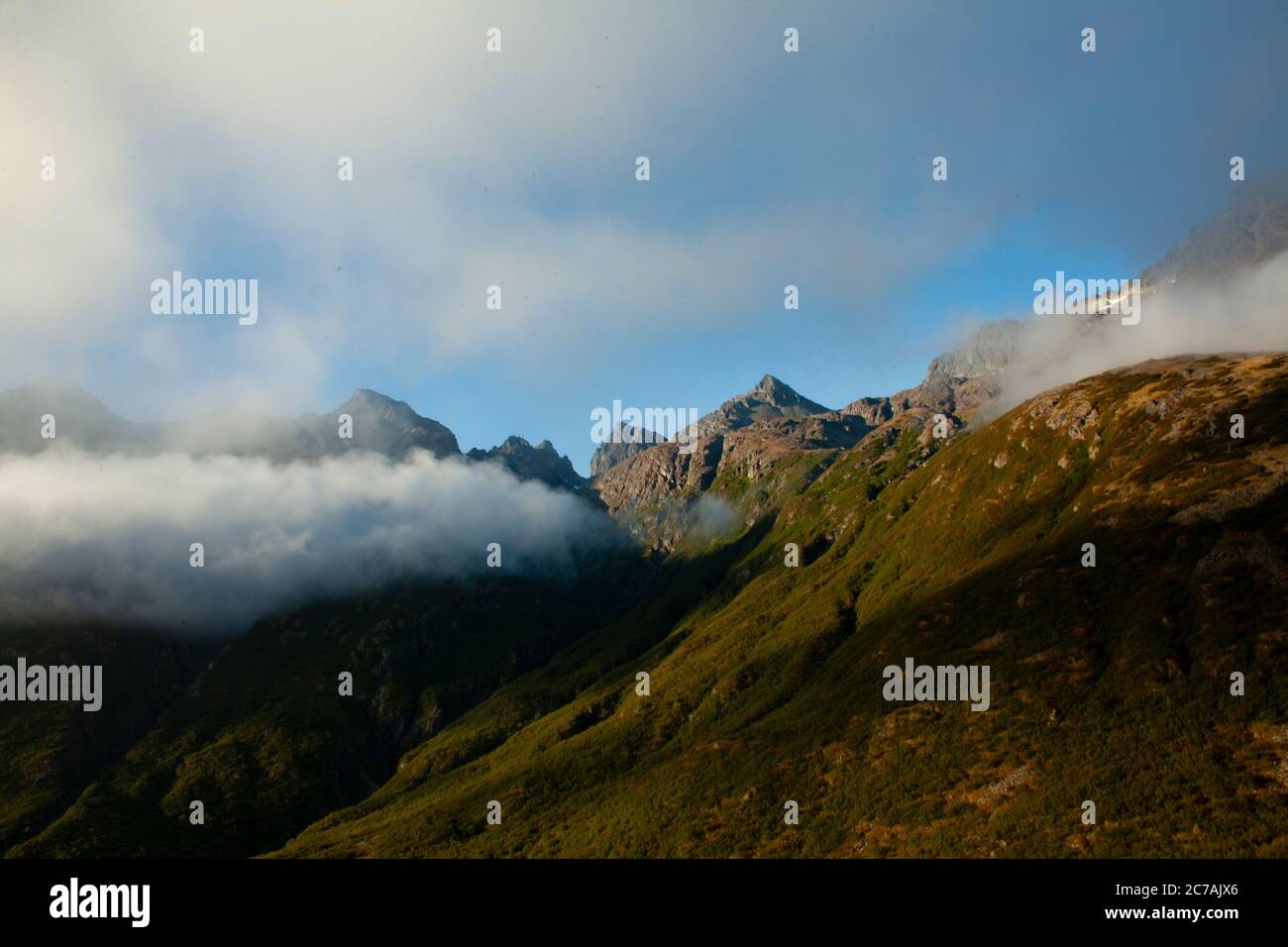 Rugged mountains in Alaska with mist rolling over the slopes, capturing ...