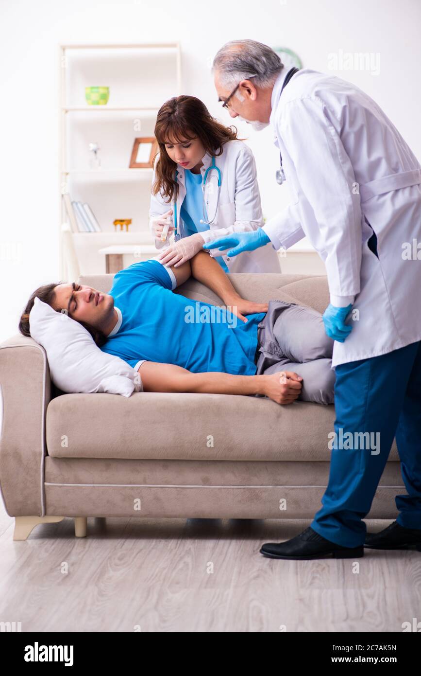 Two doctors visiting sick man at home Stock Photo - Alamy