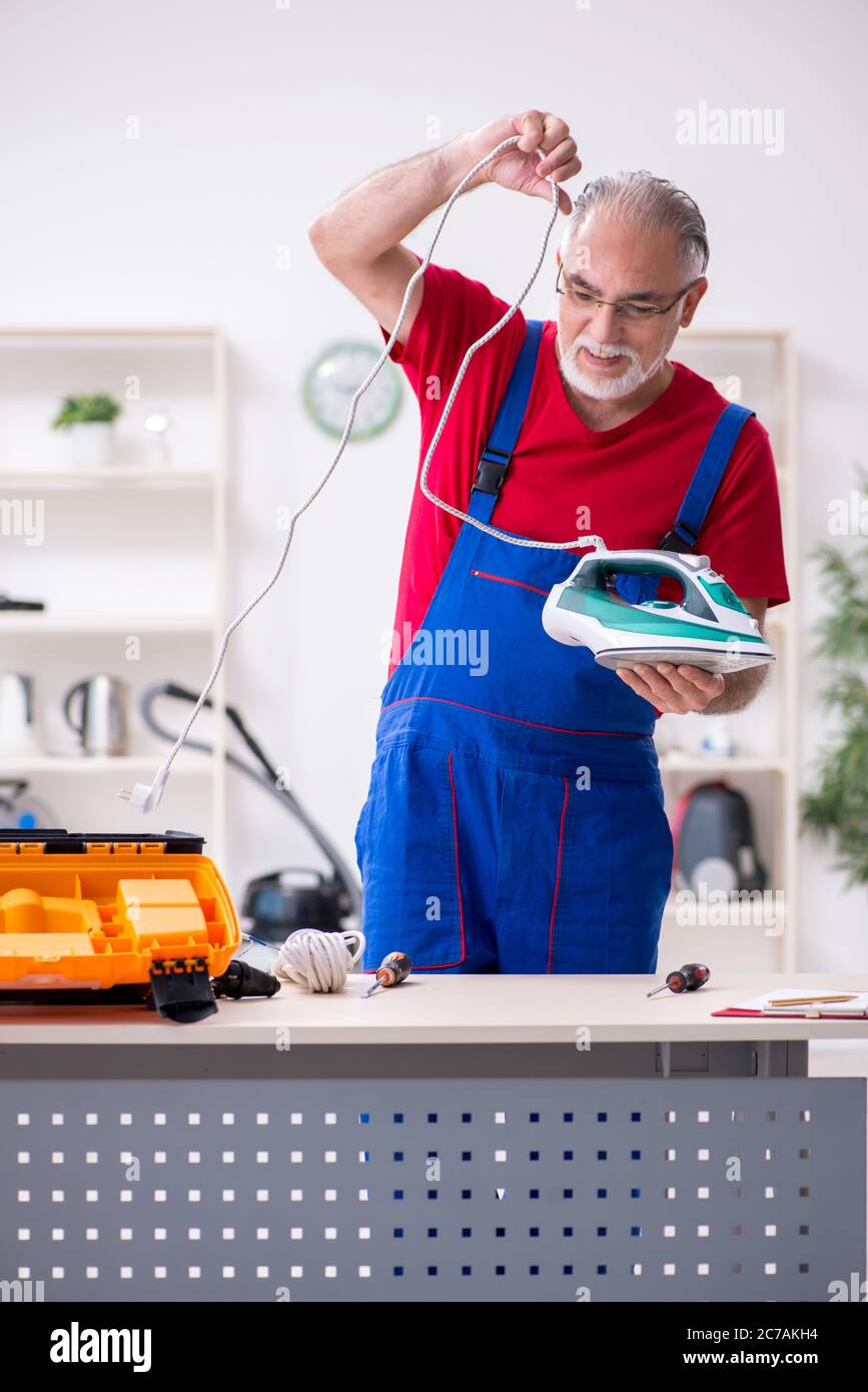 Old repairman repairing appliances in his workshop Stock Photo - Alamy