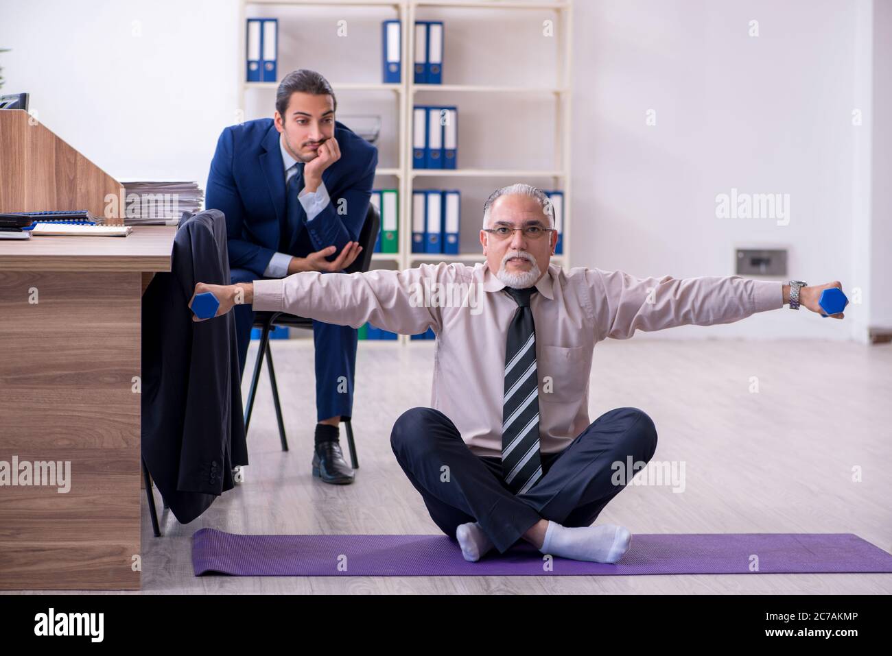 Two employees doing physical exercises at the workplace Stock Photo - Alamy