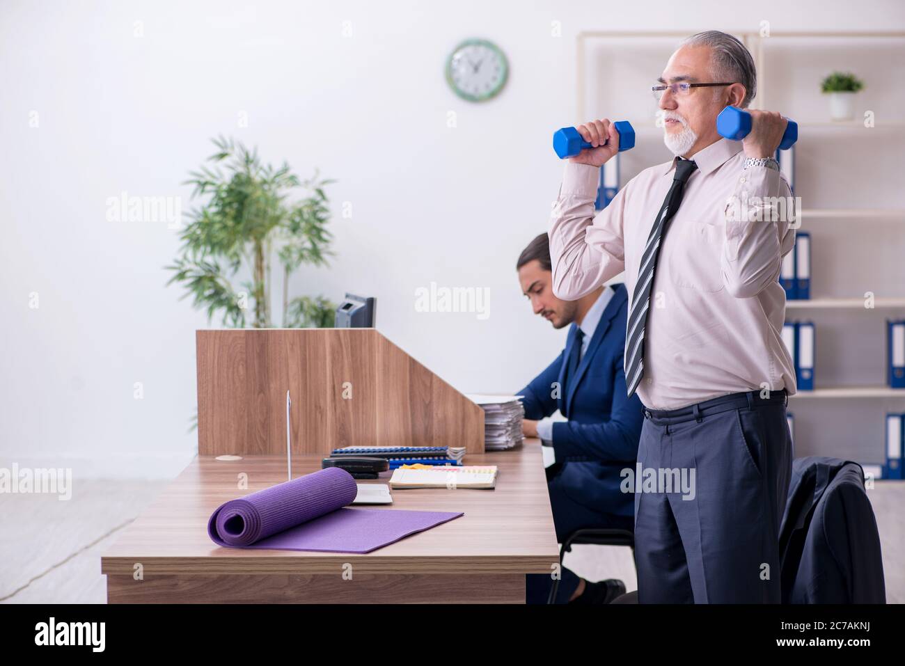 Two employees doing physical exercises at the workplace Stock Photo - Alamy