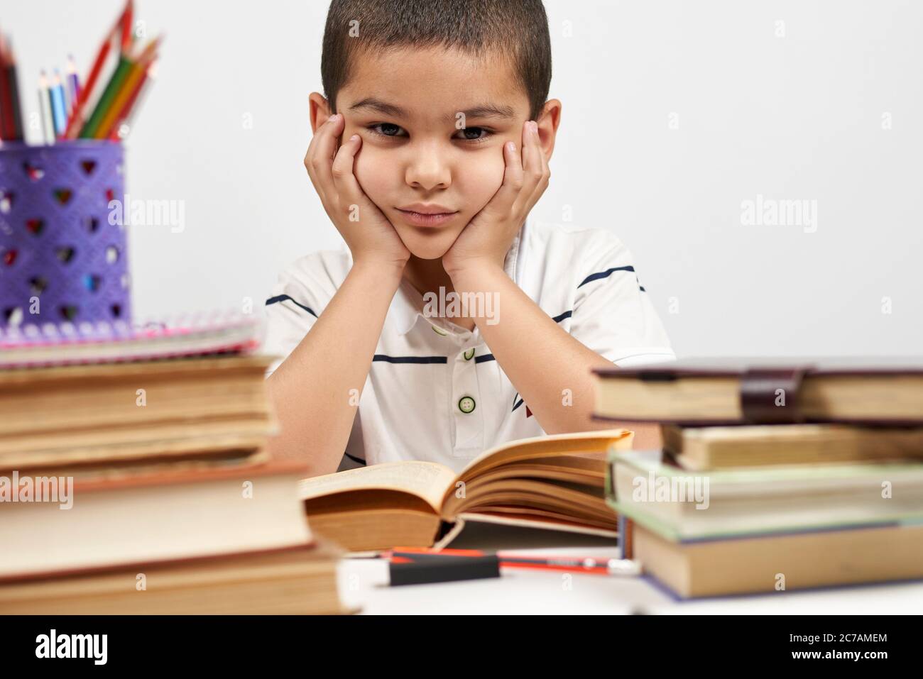 Bored schoolboy. A boy looking tired of doing homework. Mixed-race kid ...