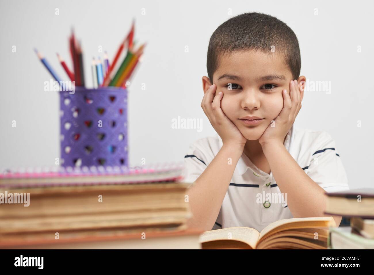 Bored schoolboy. A boy looking tired of doing homework. Mixed-race kid ...