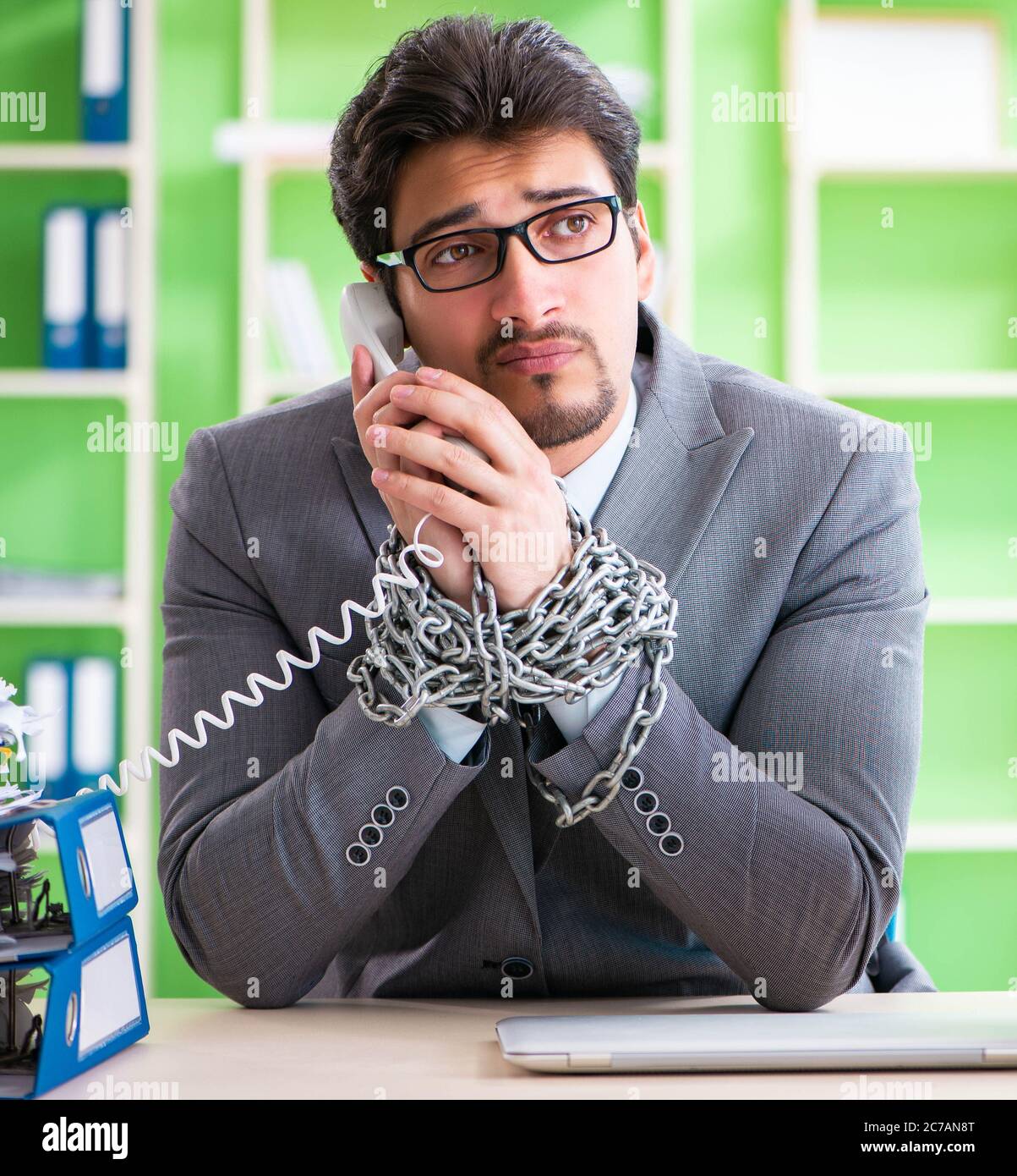 The employee chained to his desk due to workload Stock Photo - Alamy