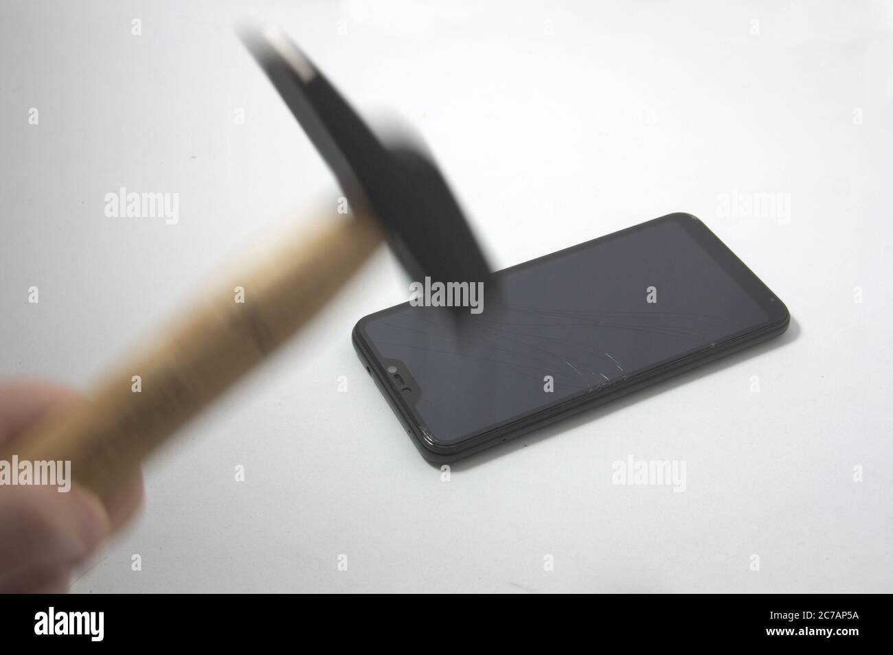 Close-up of a moving hammer that has broken the screen of a mobile that ...