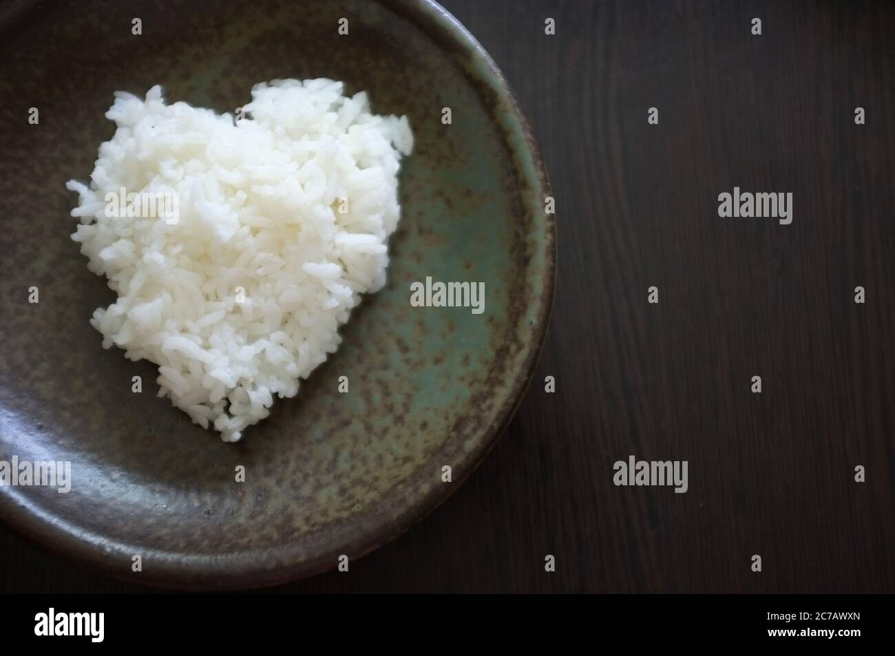 Top view heart shape of cooked rice in a dish . copy space for text ...