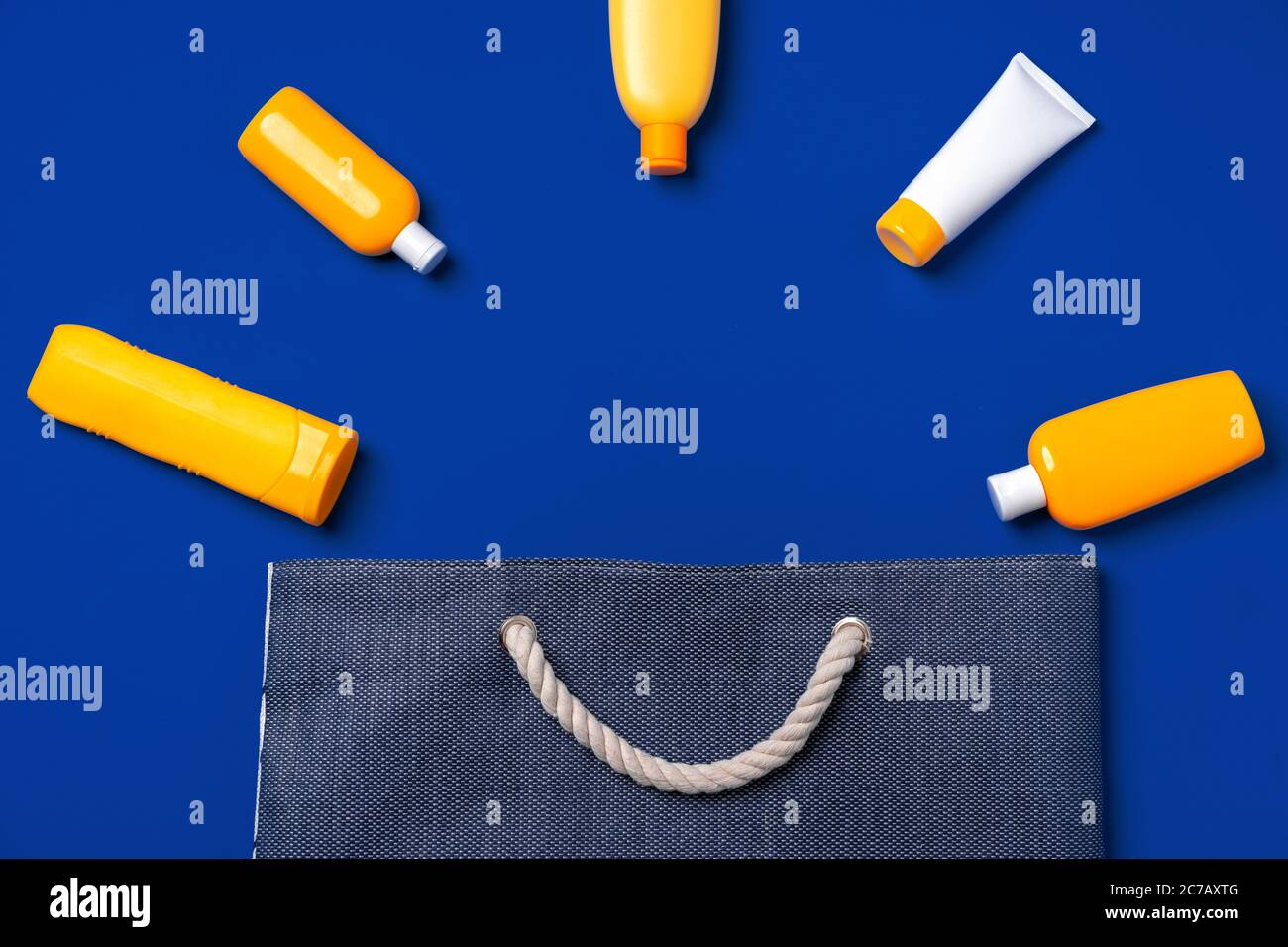 Bright yellow bottles of sunscreen product on dark blue paper ...