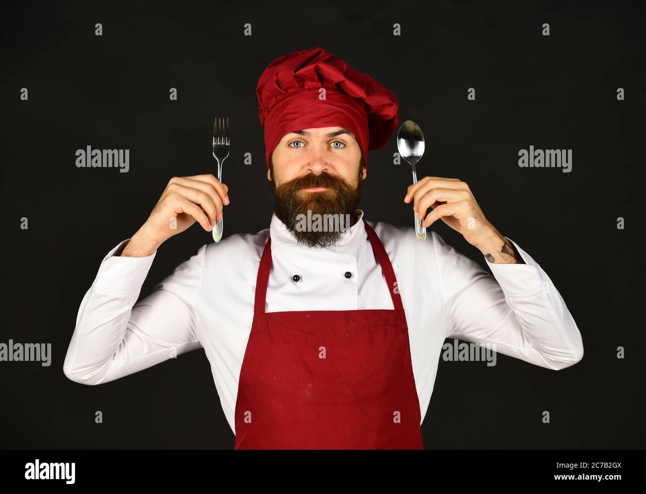 Chef holds cutlery. Kitchen utensils concept. Man with beard holds ...