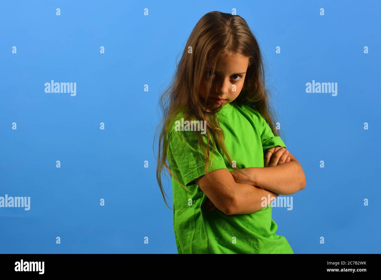 Girl with arrogant and grumpy face on blue background. Child looks like ...