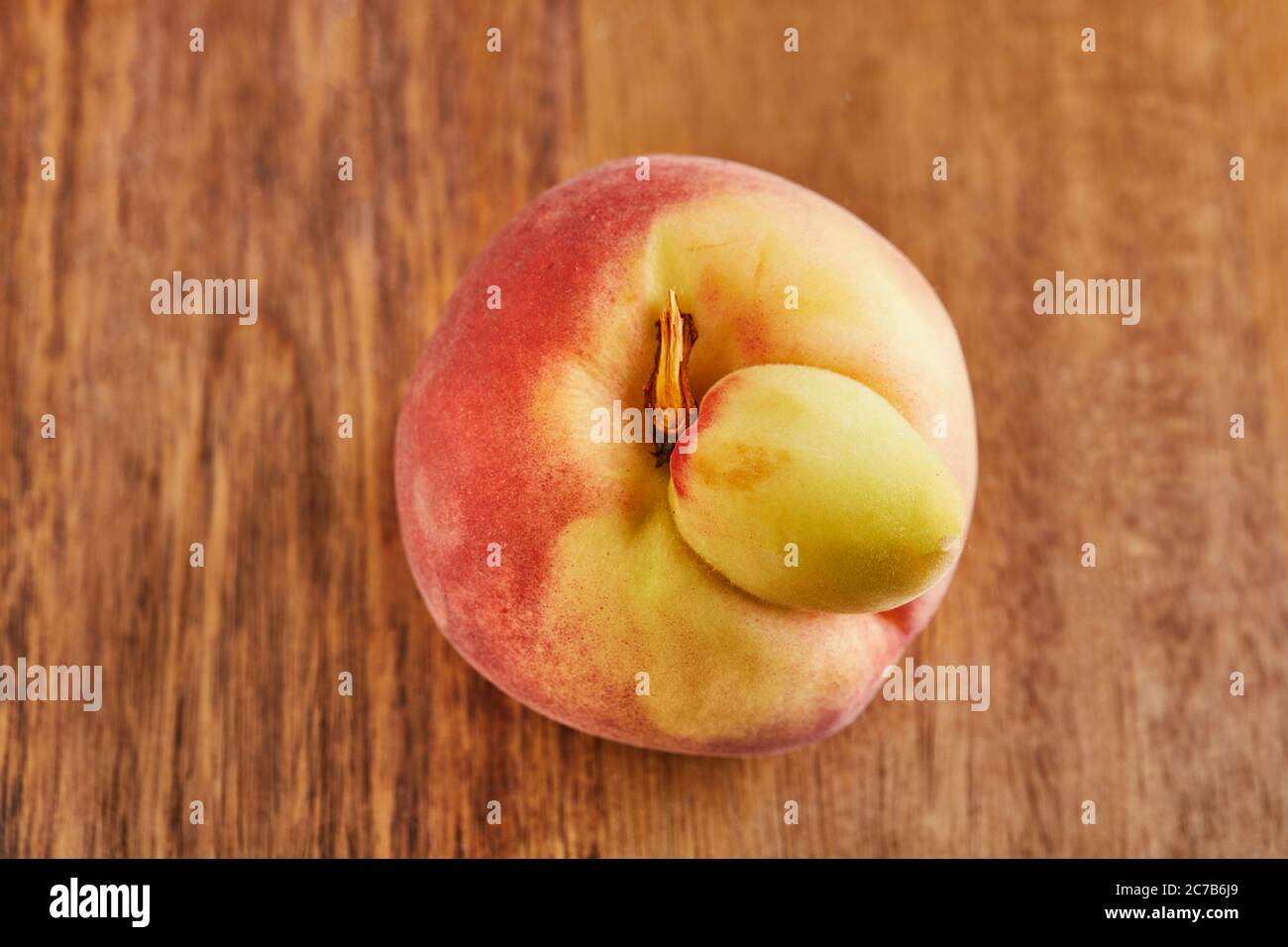 ugly fruit or vegetable. Heavily ugly peach mutant on a wooden ...