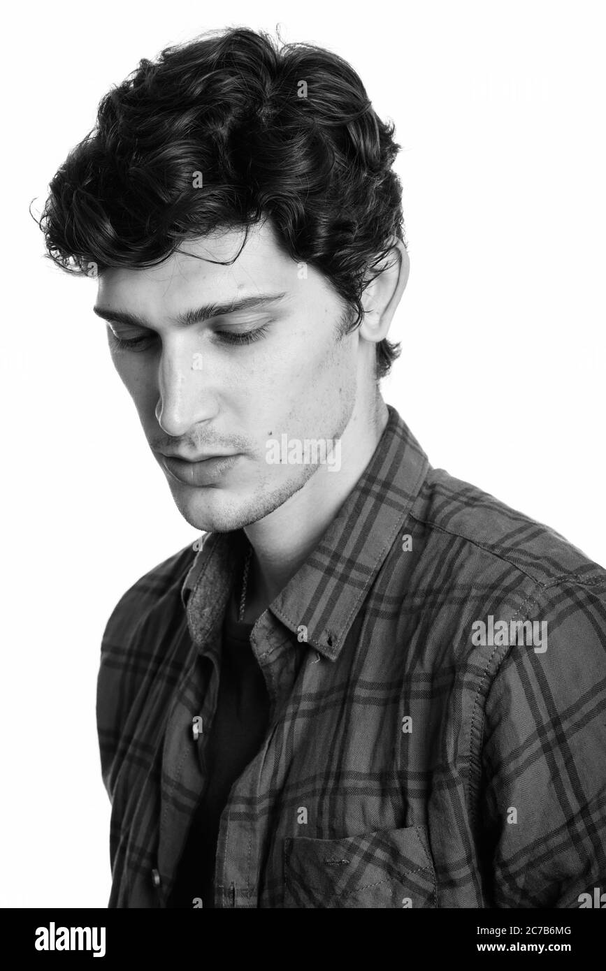 Face of young handsome man thinking while looking down Stock Photo - Alamy