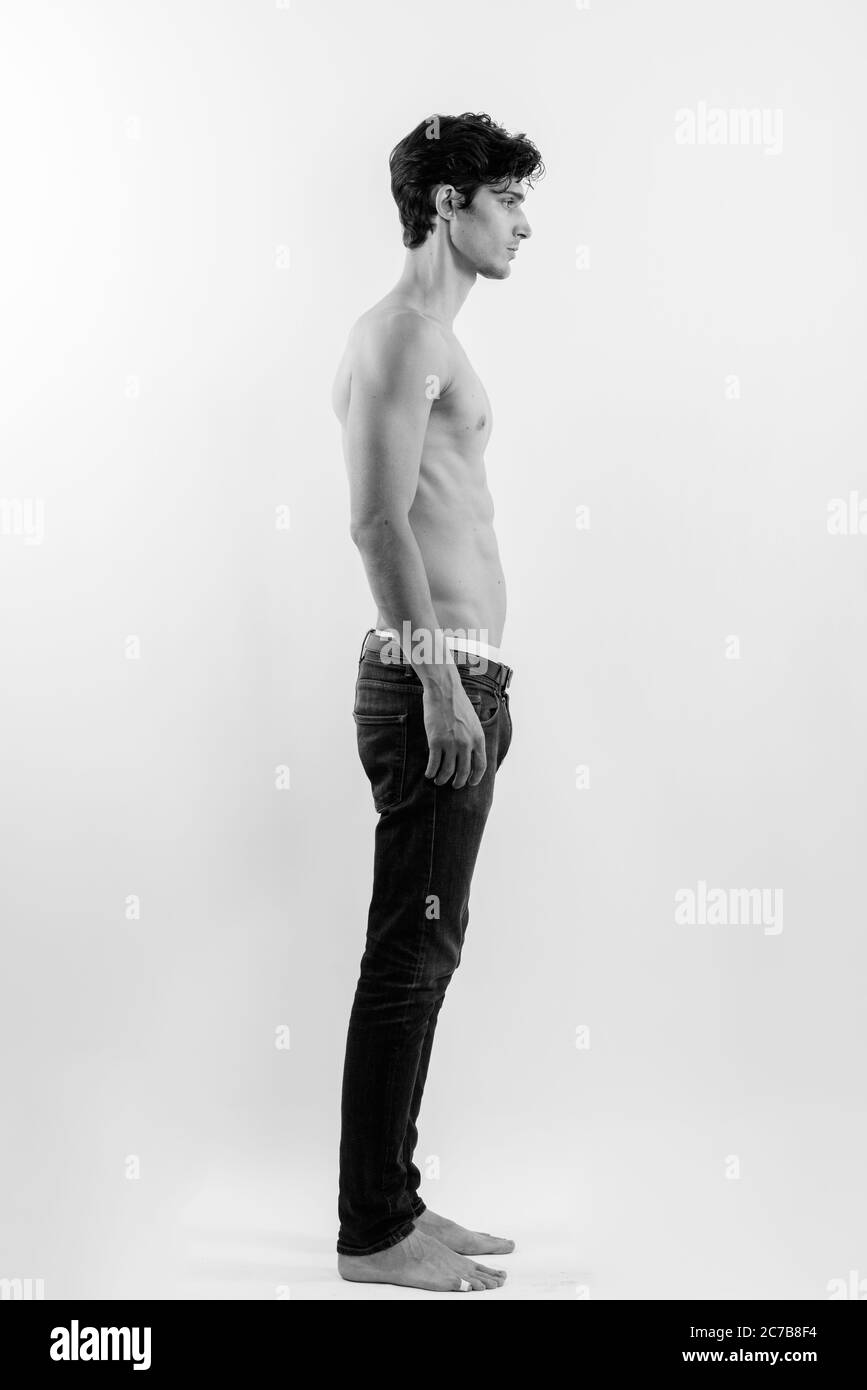 Full body shot of profile view of young handsome man standing shirtless ...
