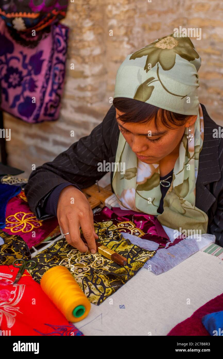 A young Uzbek woman is doing embroidery in a bazaar (a market in a ...