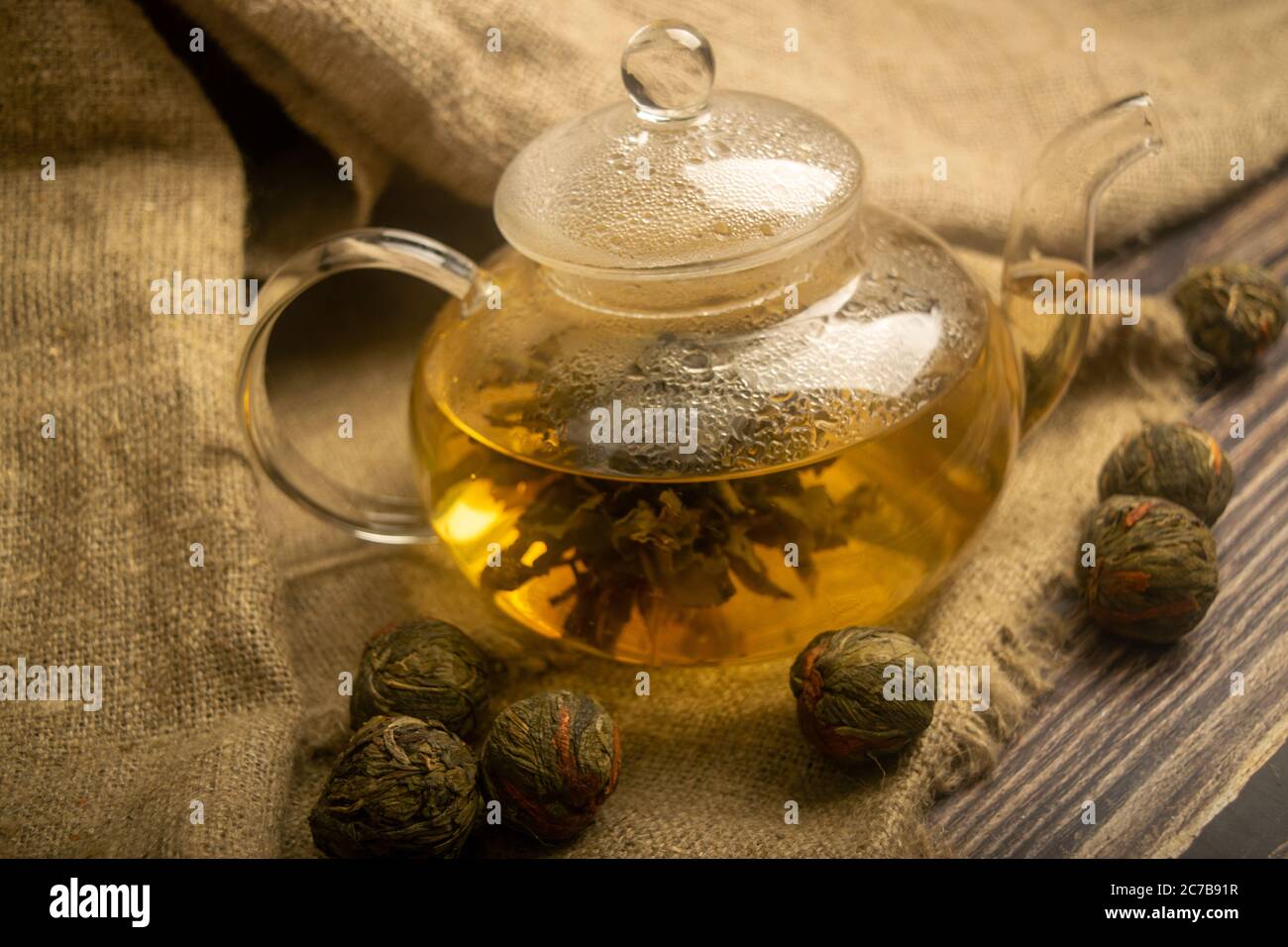 Flower tea brewed in a glass teapot on a background of homespun fabric ...