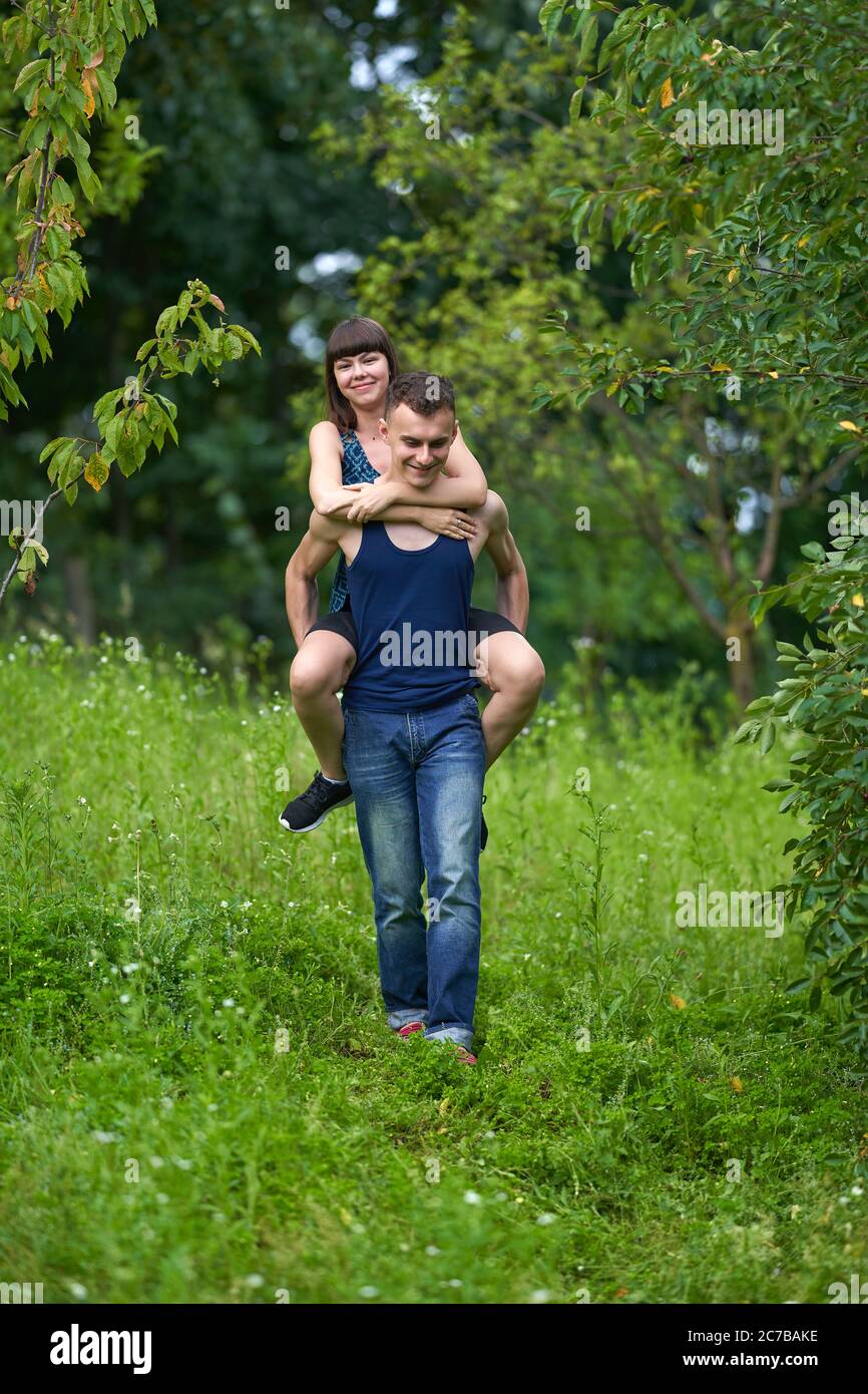 Young couple having fun with a piggyback ride outdoor in the nature ...