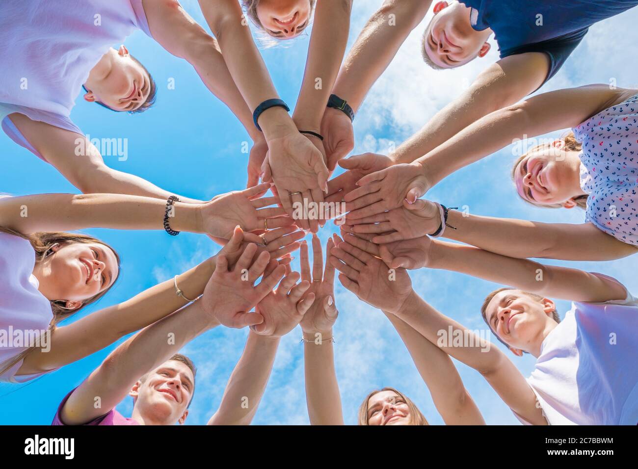 Cheerful friendly friends align their hands in the center. Teamwork ...