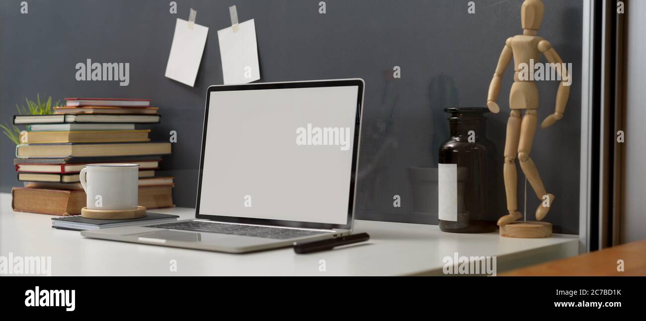 Side view of study table with mock up laptop, stack of books and ...