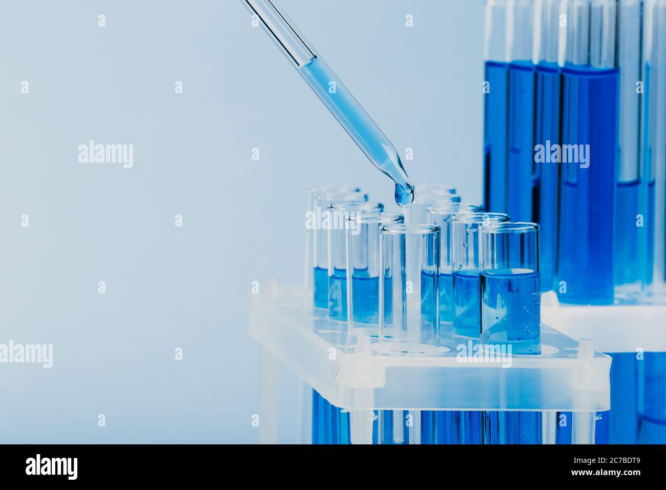 Laboratory glassware with a dropper dripping liquid into a test tube ...