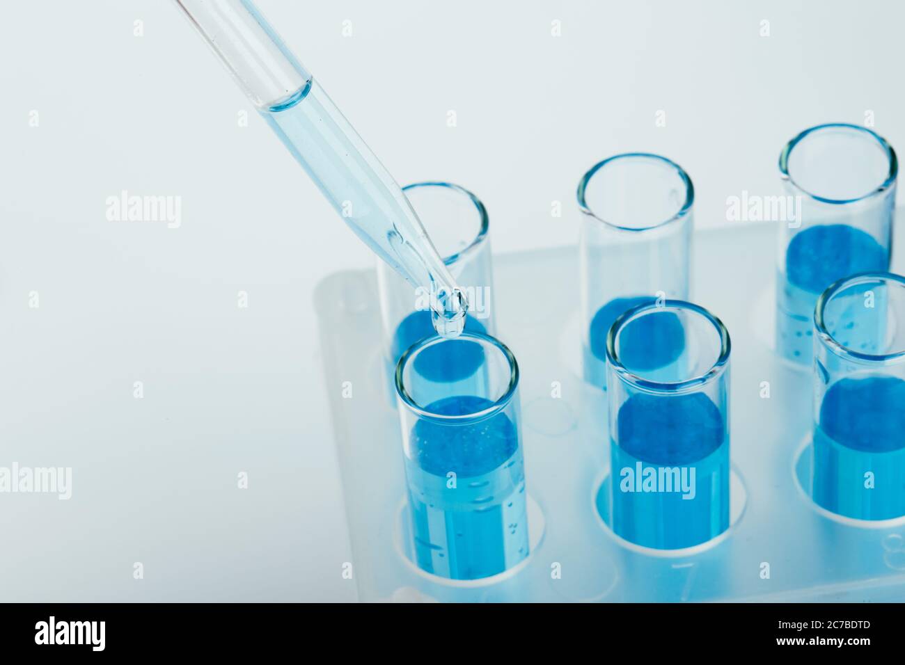 Laboratory glassware with a dropper dripping liquid into a test tube ...