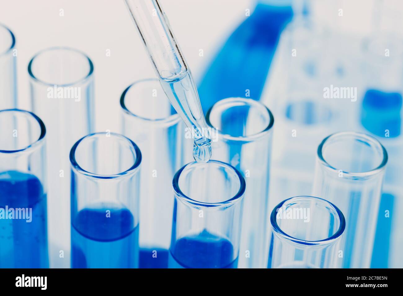 Laboratory glassware with a dropper dripping liquid into a test tube ...