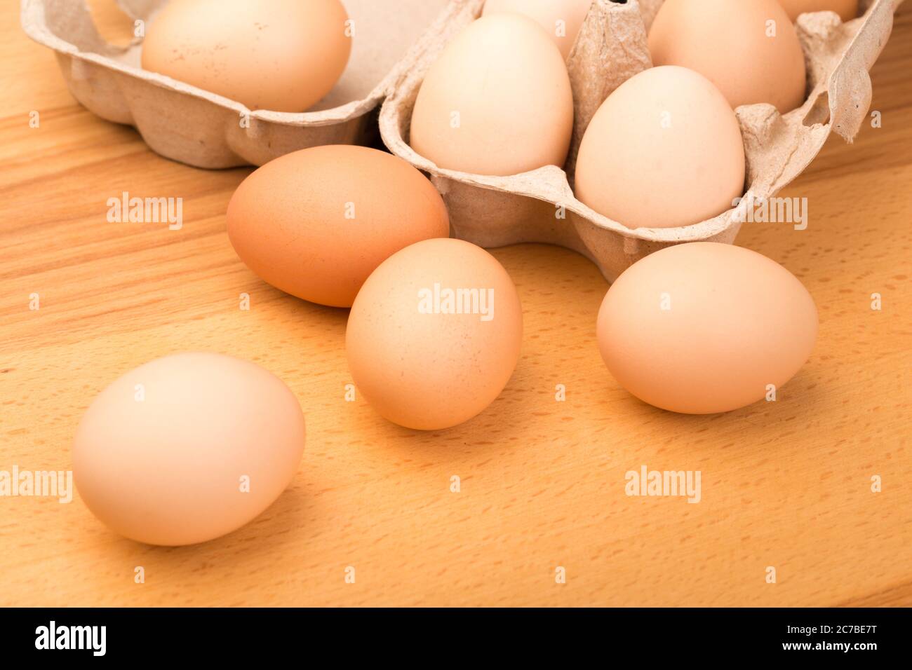 brown chicken eggs in an open cardboard box with eggs on a wooden table ...