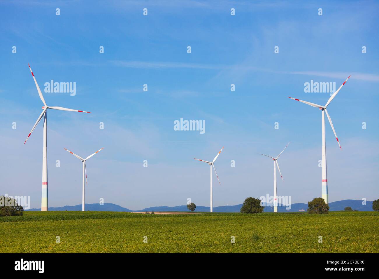 Rotating wind wheels on farmland against blue sky Stock Photo - Alamy