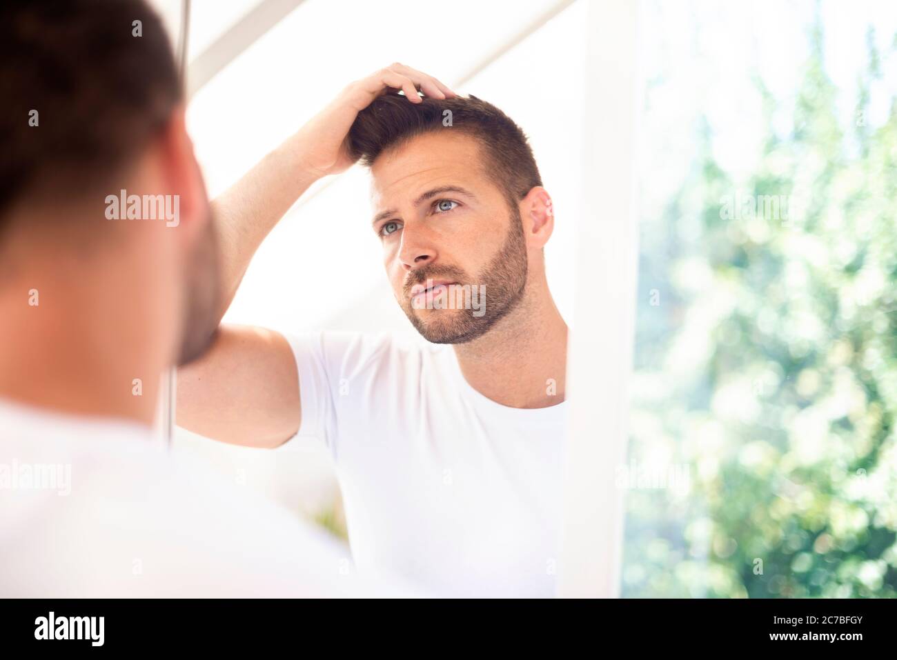 Close-up shot of a handsome young man admiring looking at his face in ...