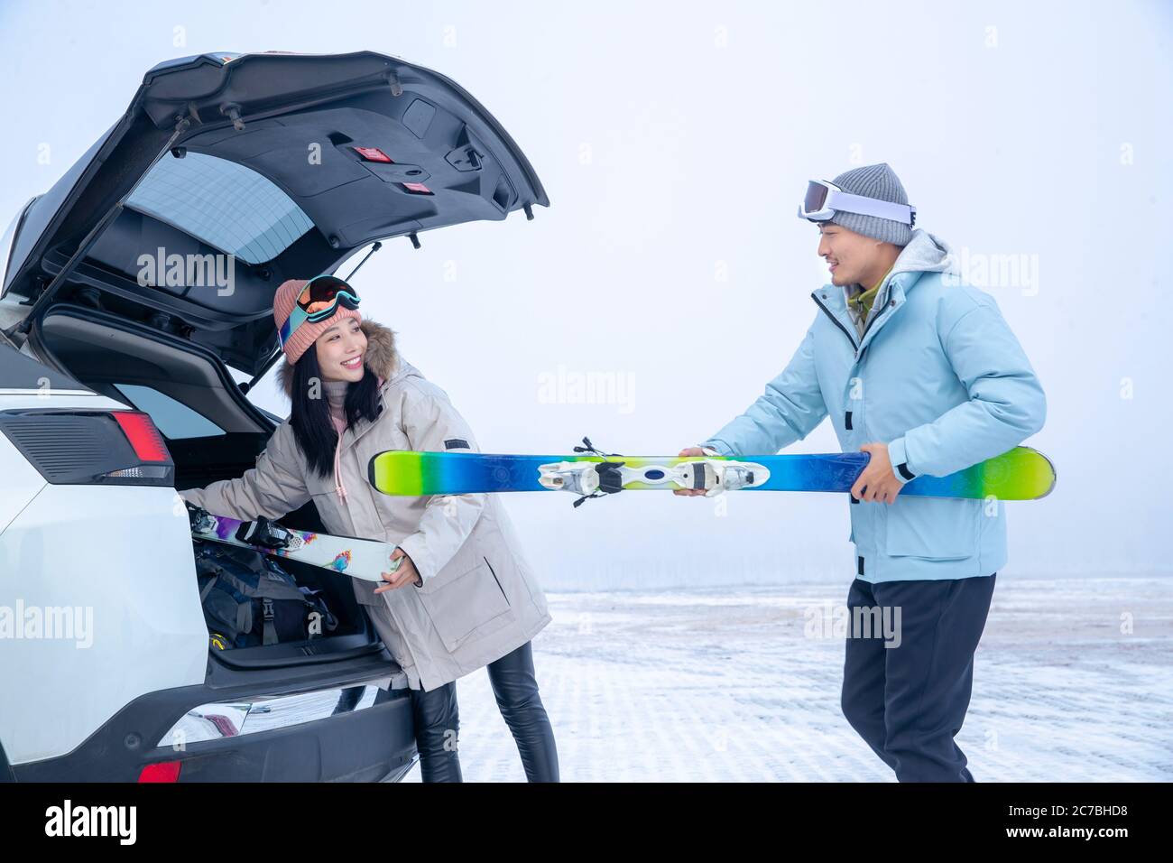 Young couples the propeller-heads to put the skis on the car trunk ...