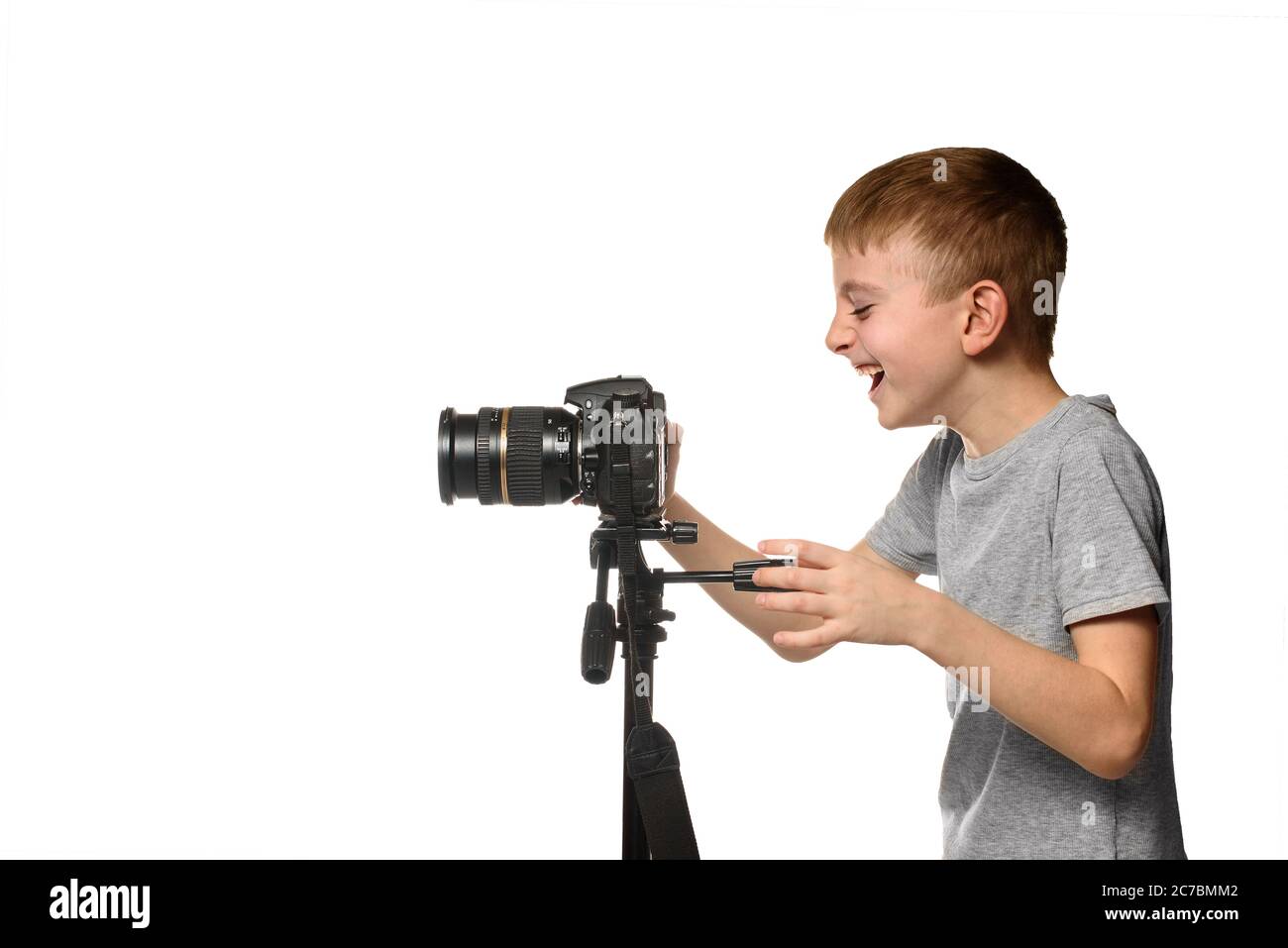 Laughing schoolboy shoots video on DSLR camera. Side view. White ...