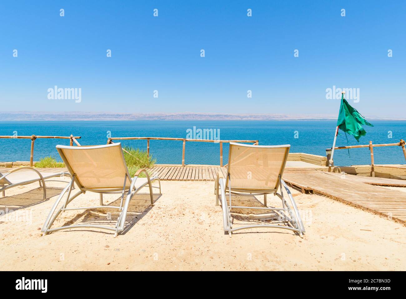 Rear view of two lounge chairs or tanning beds set on a sand terrace in ...