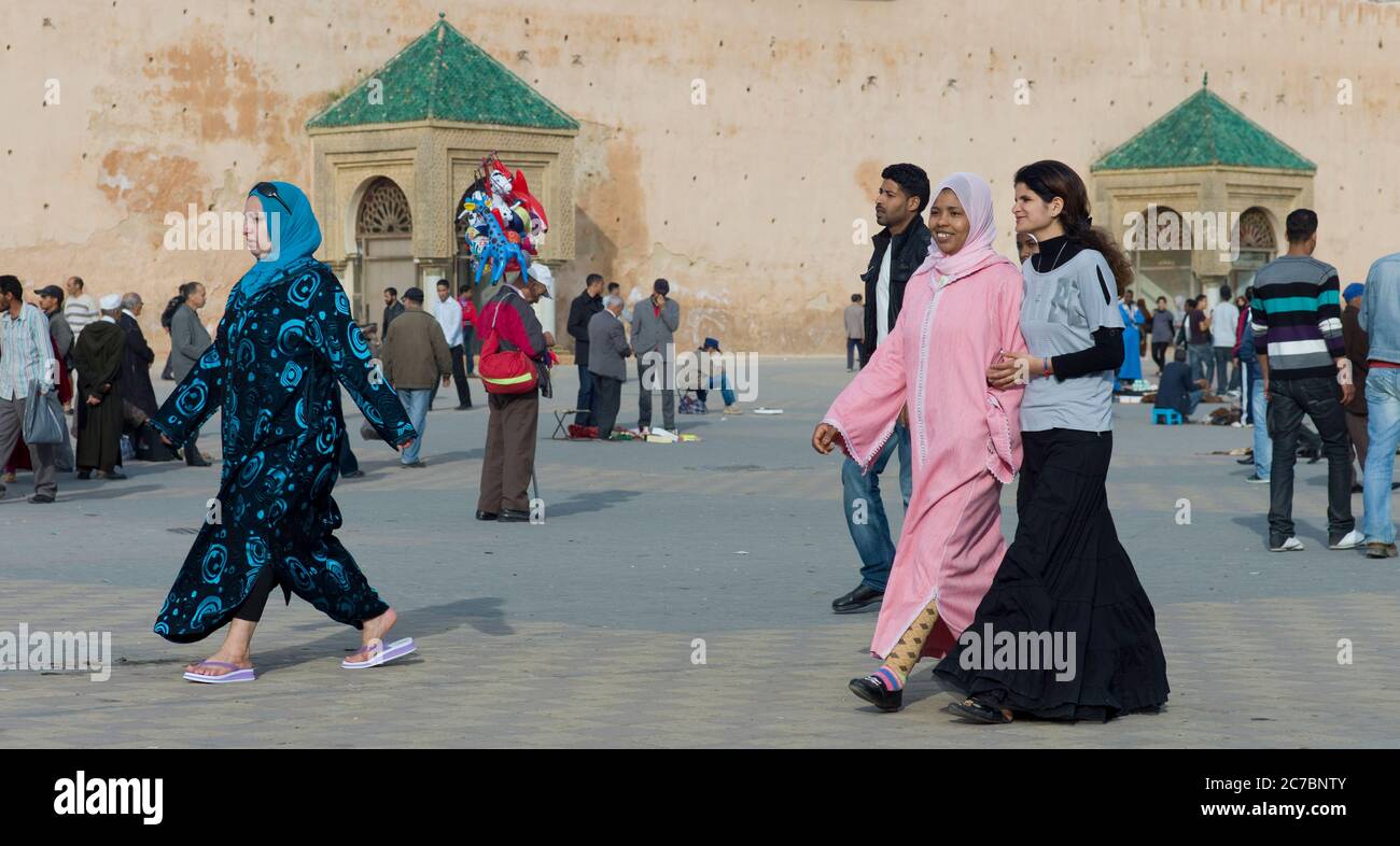 Arabic women with djellaba walking on square near he city wall in the ...