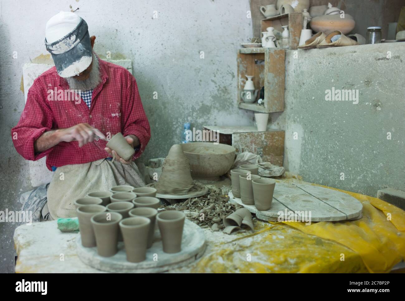 Old unrecognizable moroccan man forms clay cups in a pottery factory in ...