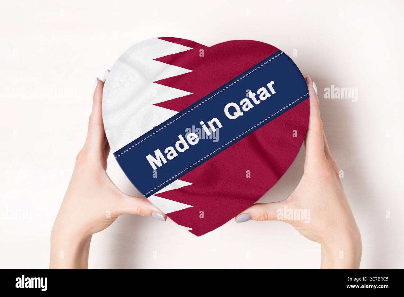 Inscription Made in Qatar the flag of Qatar. Female hands holding a ...