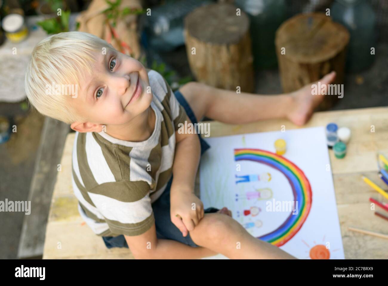 Cute boy draws rainbow and family. Open air. Top view. Creative concept ...
