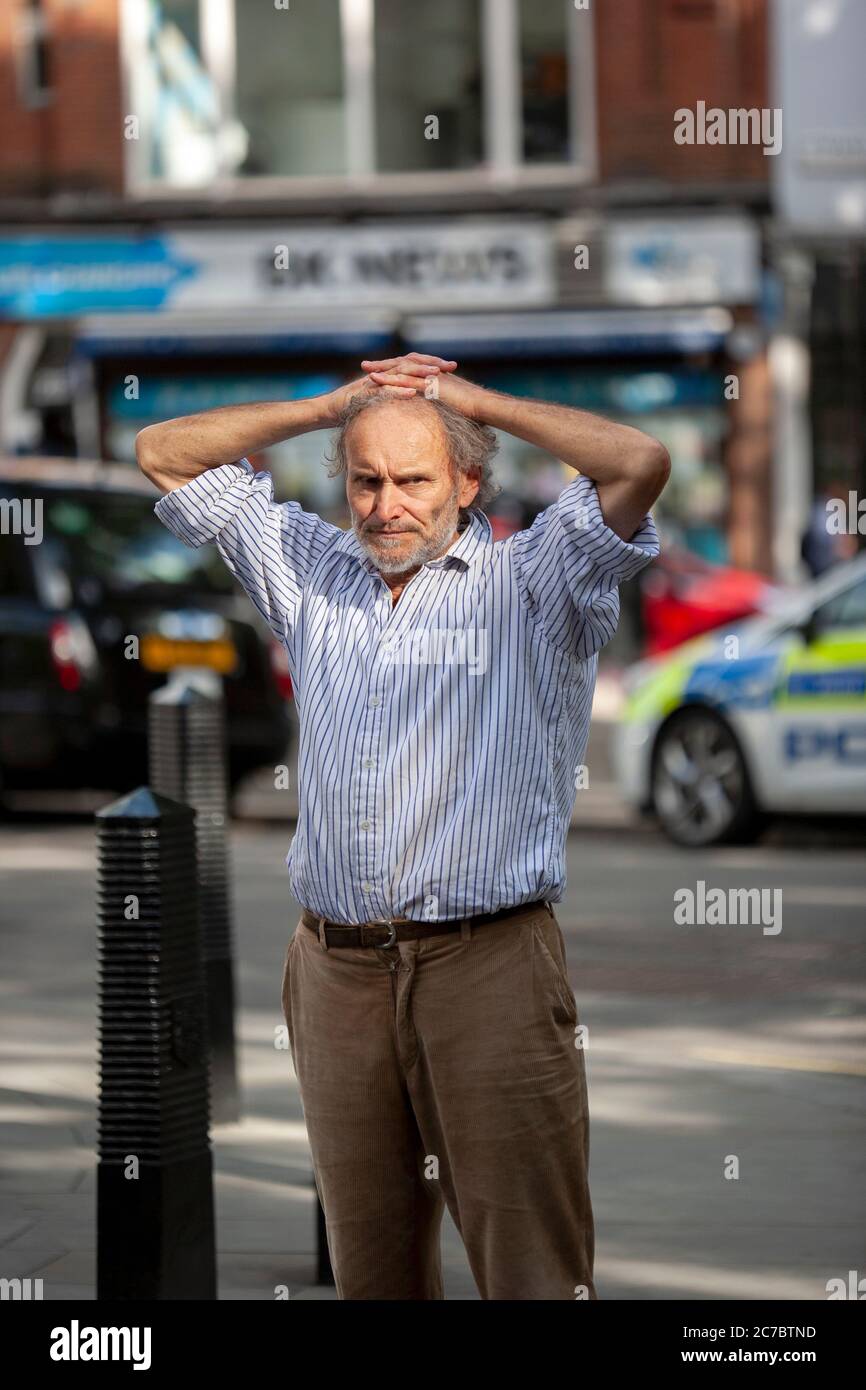 A middle-aged man stands exasperated with hands on head outside the ...