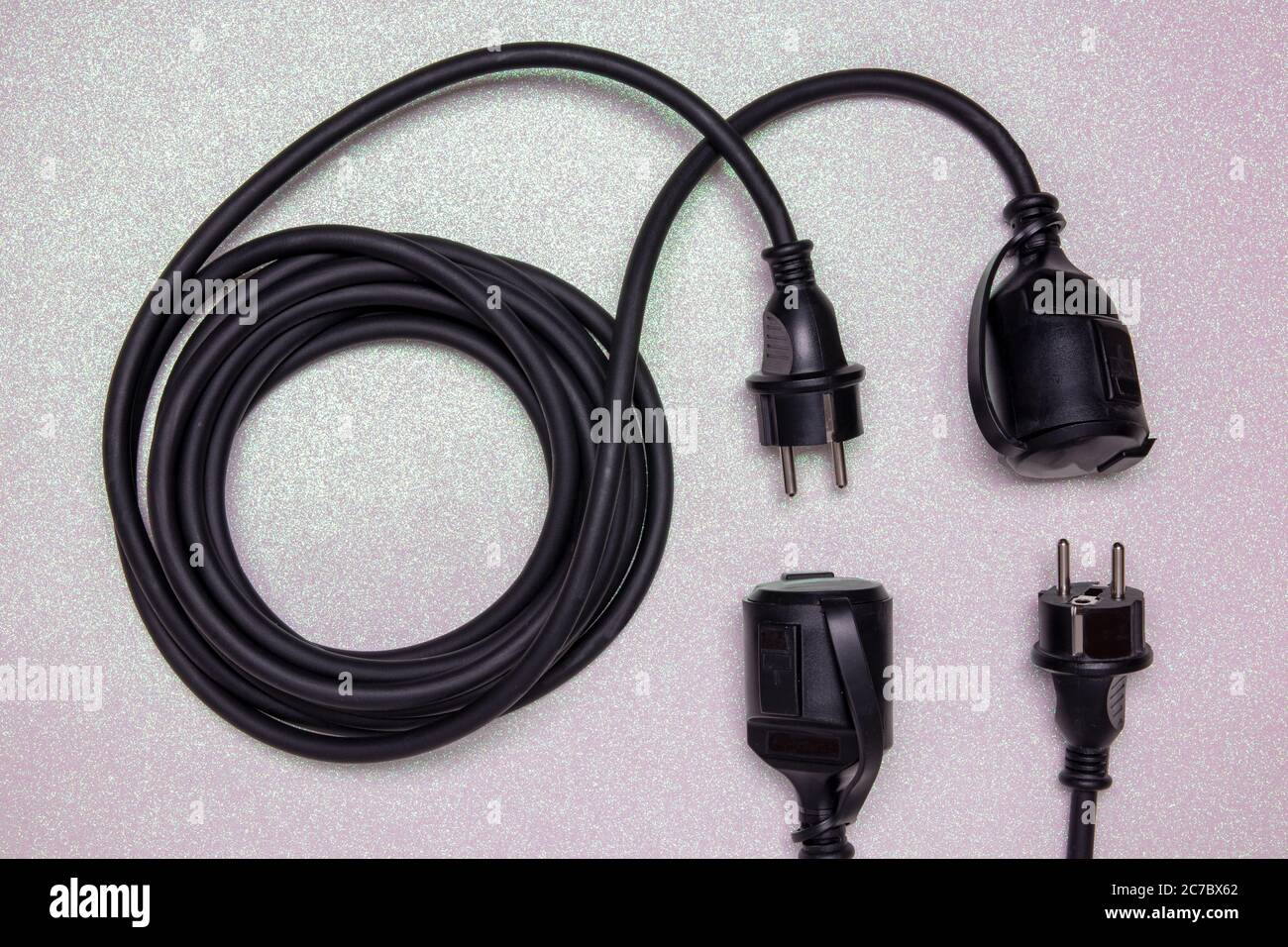 Closeup of a coiled black electric power extension cable with a further ...