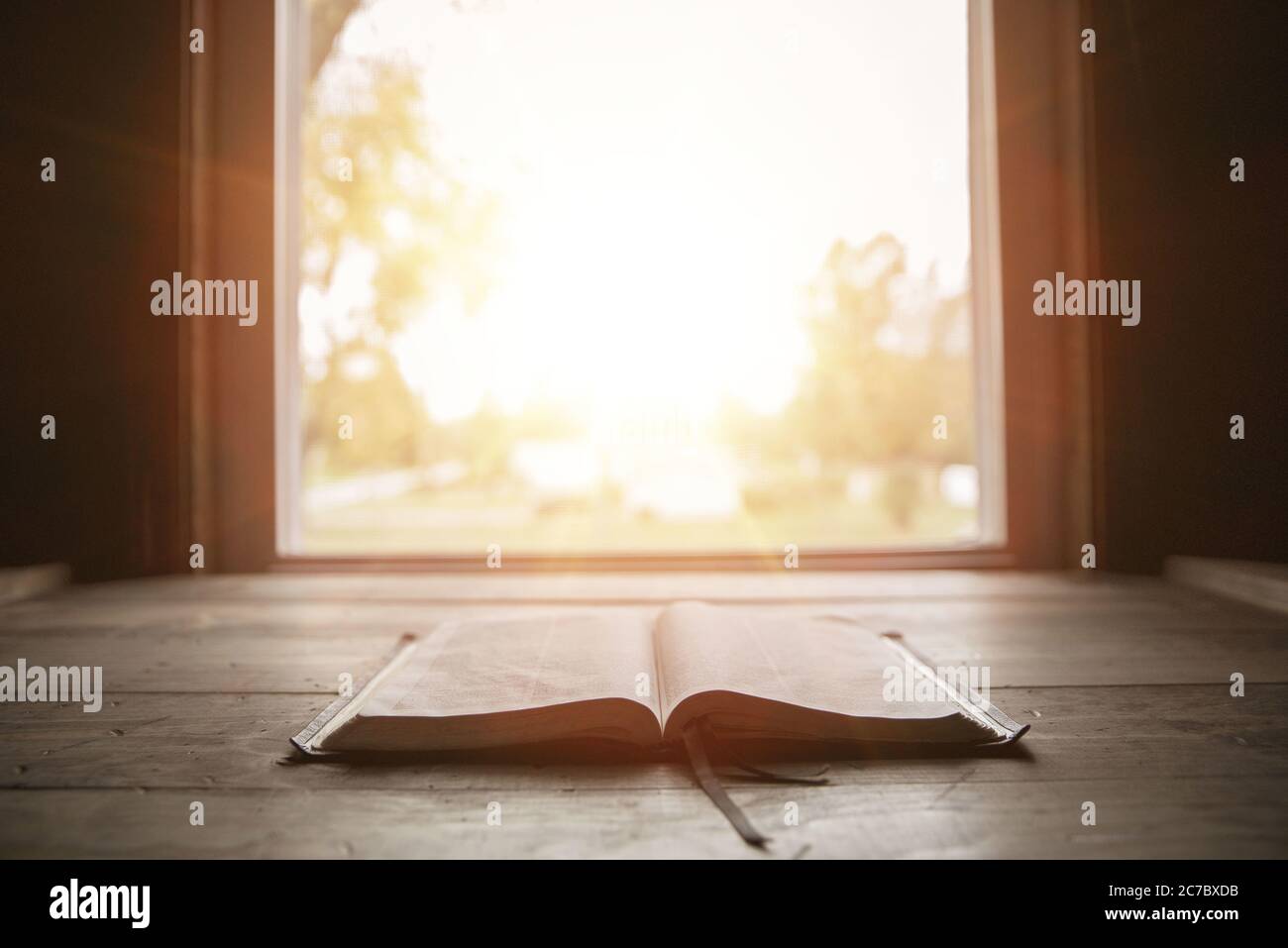 Close shot of holy bible on a wooden surface with the sun shining in ...