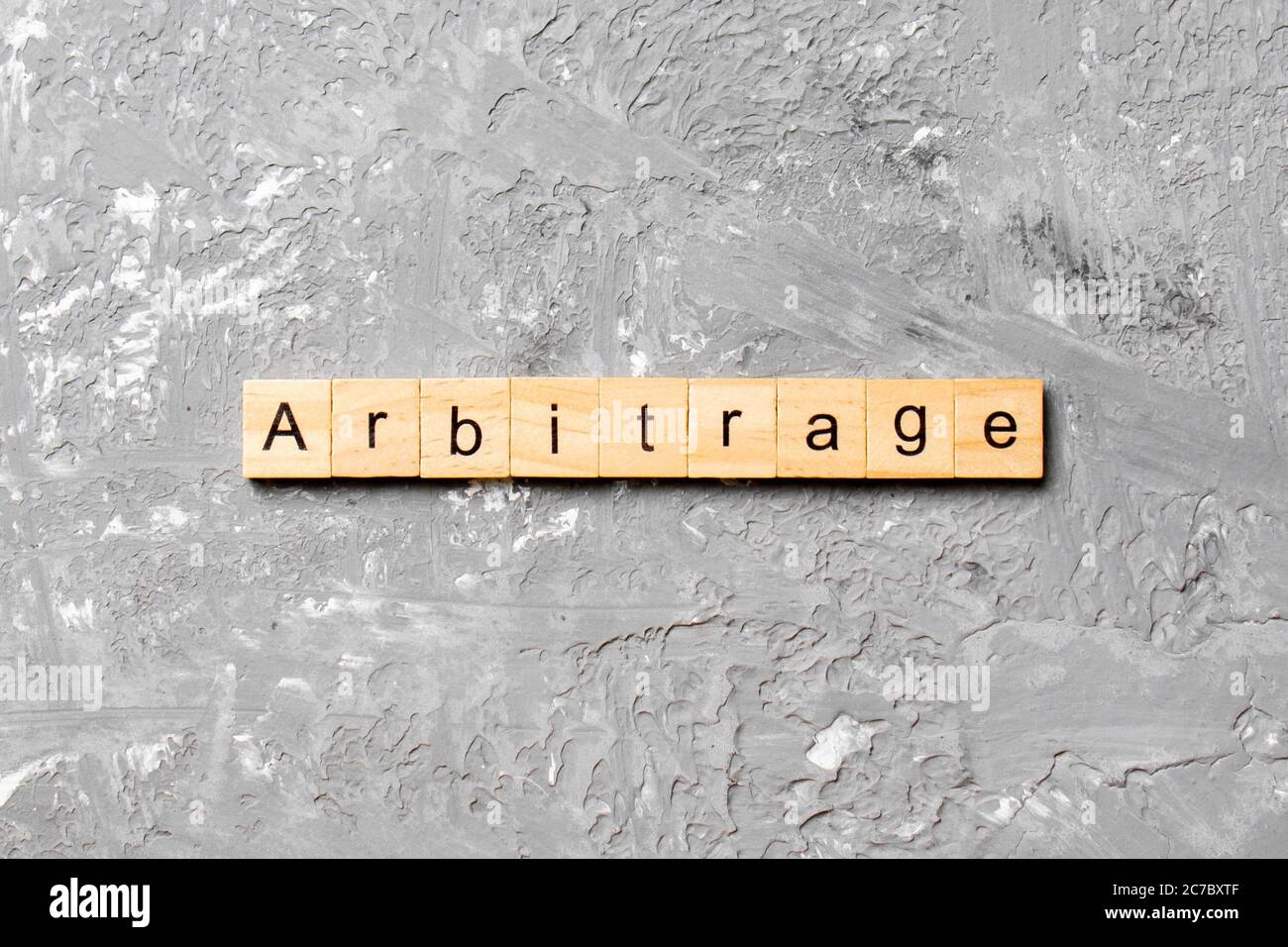 Arbitrage word written on wood block. Arbitrage text on cement table ...