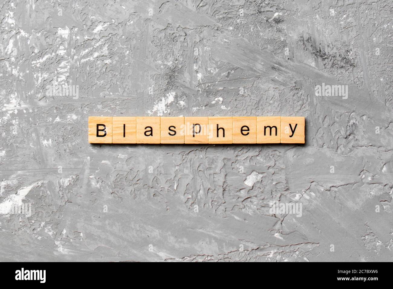 BLASPHEMY word written on wood block. BLASPHEMY text on cement table ...