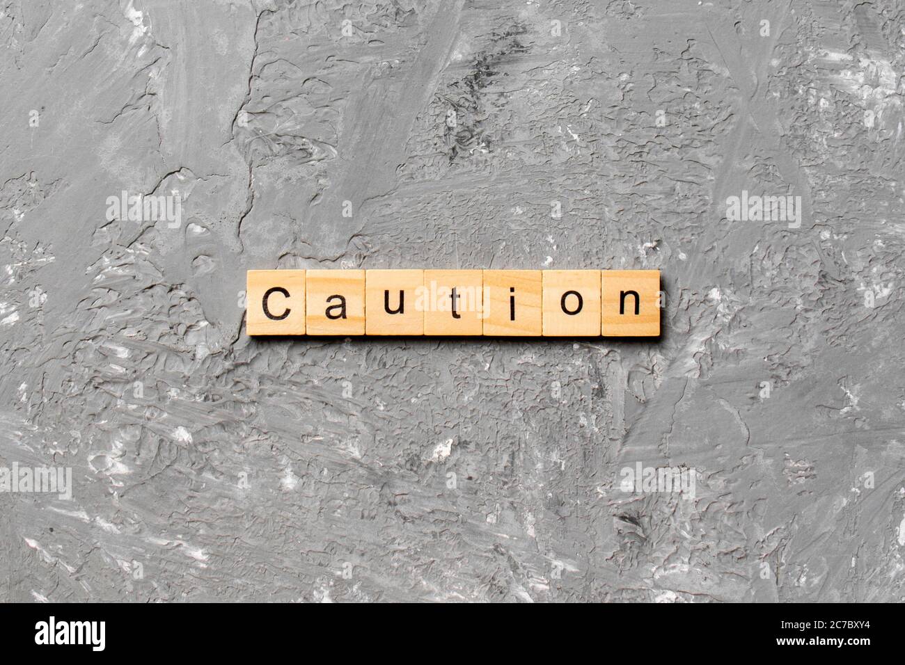 CAUTION word written on wood block. CAUTION text on cement table for ...