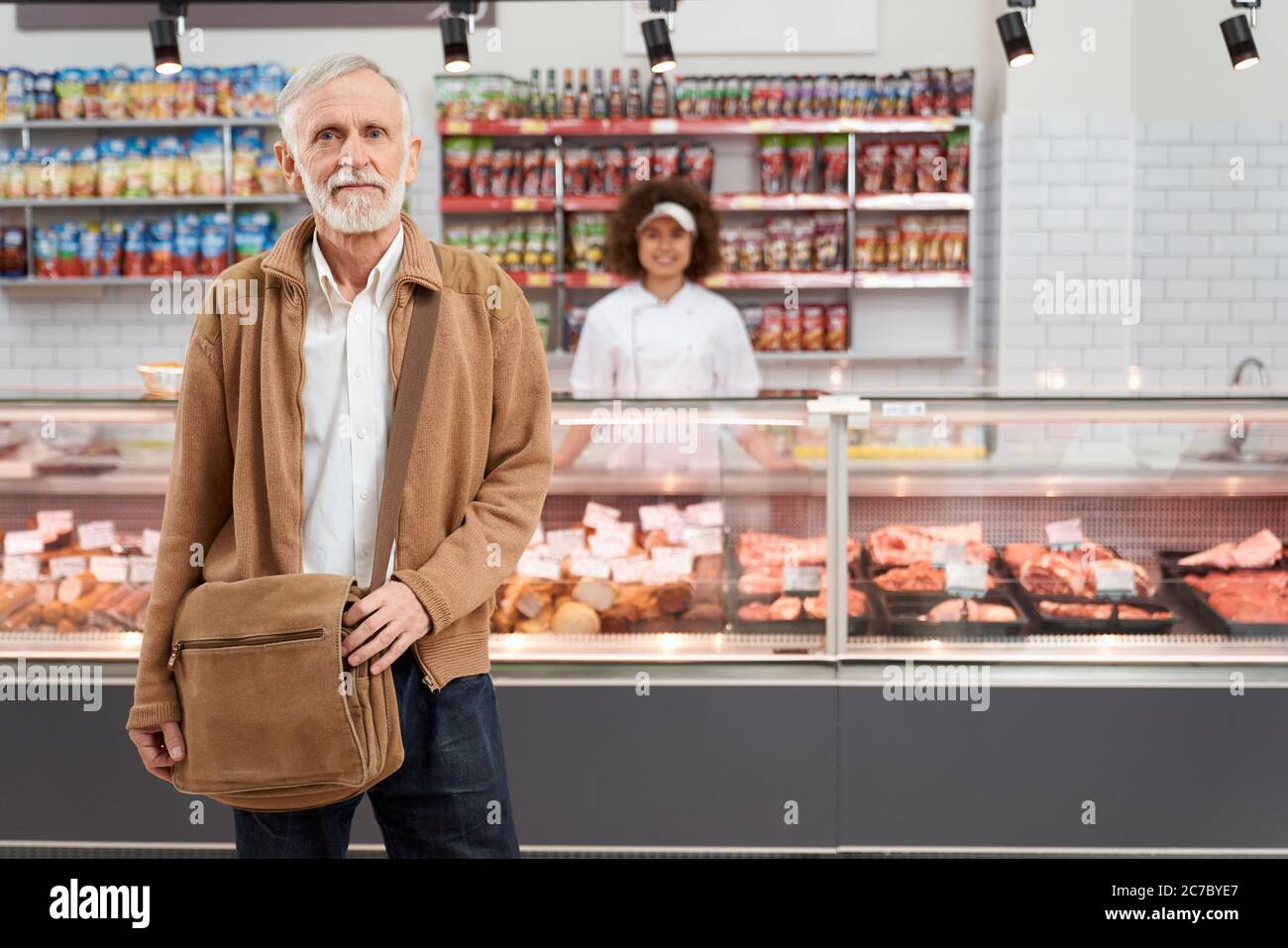 Front view of cheerful girl with curly hair near store counter with big ...